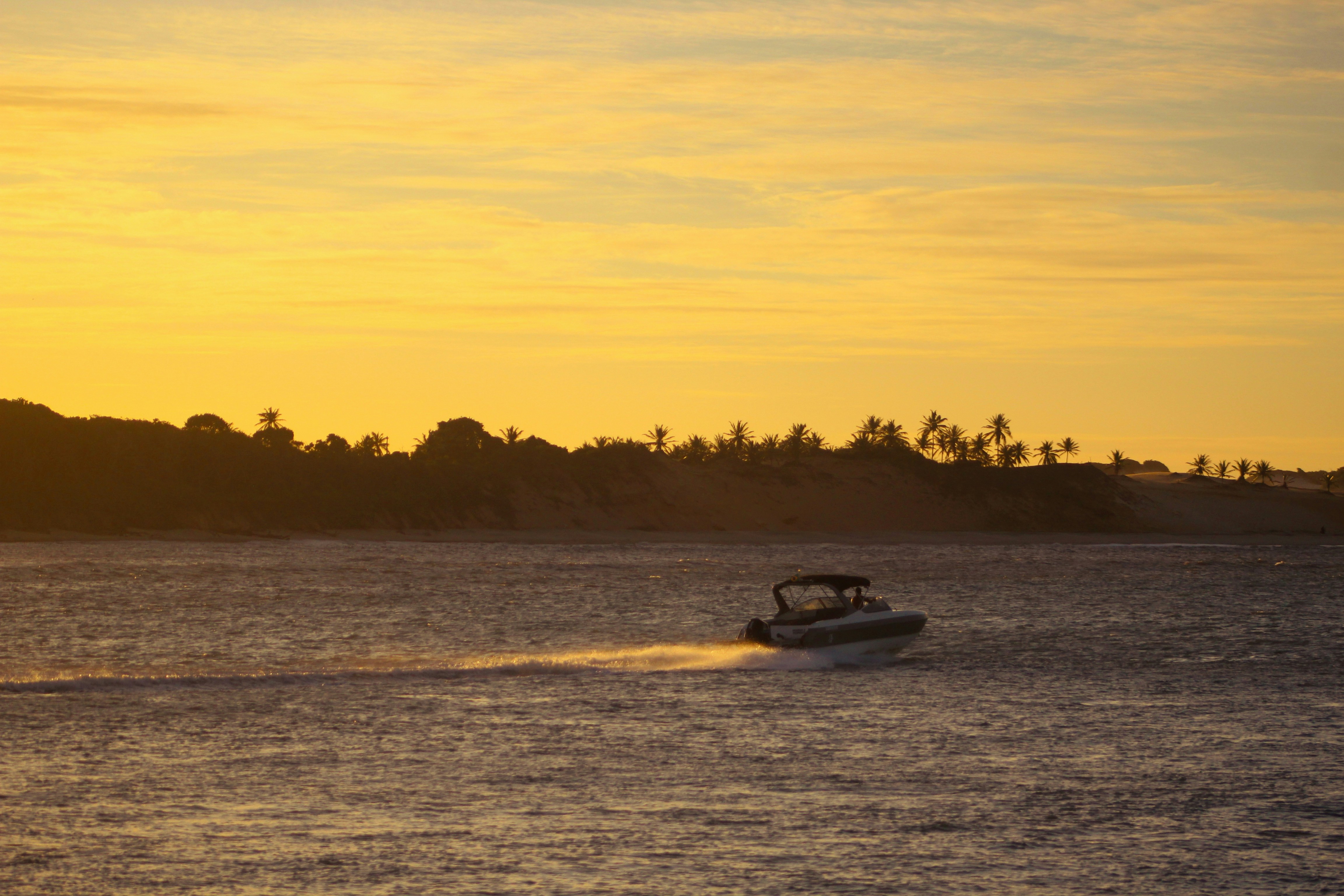 Golden Hour Sail: Boat Cutting Through a Glowing Bay