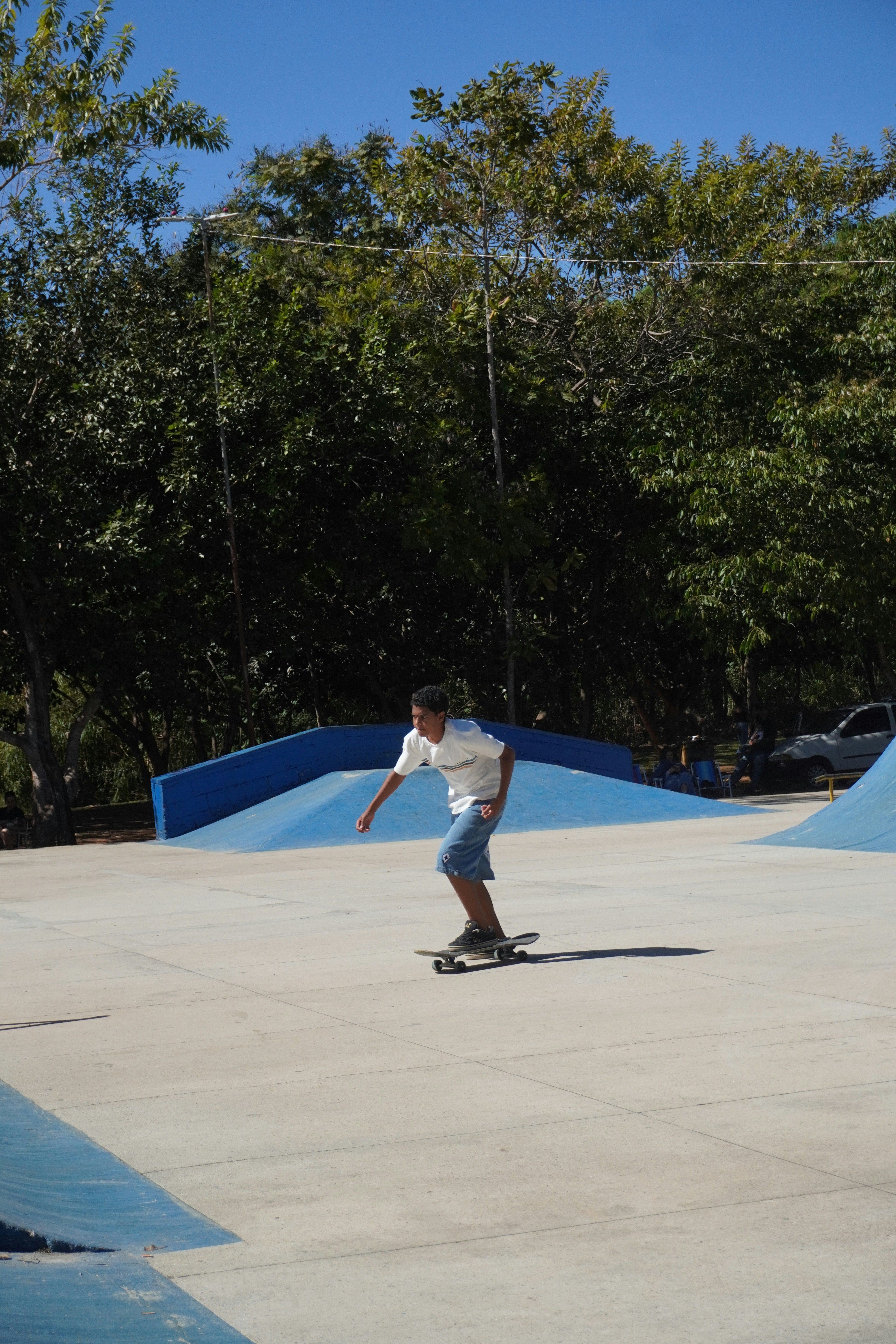 Skateboarder in a sunlit park ramps through a concrete course
