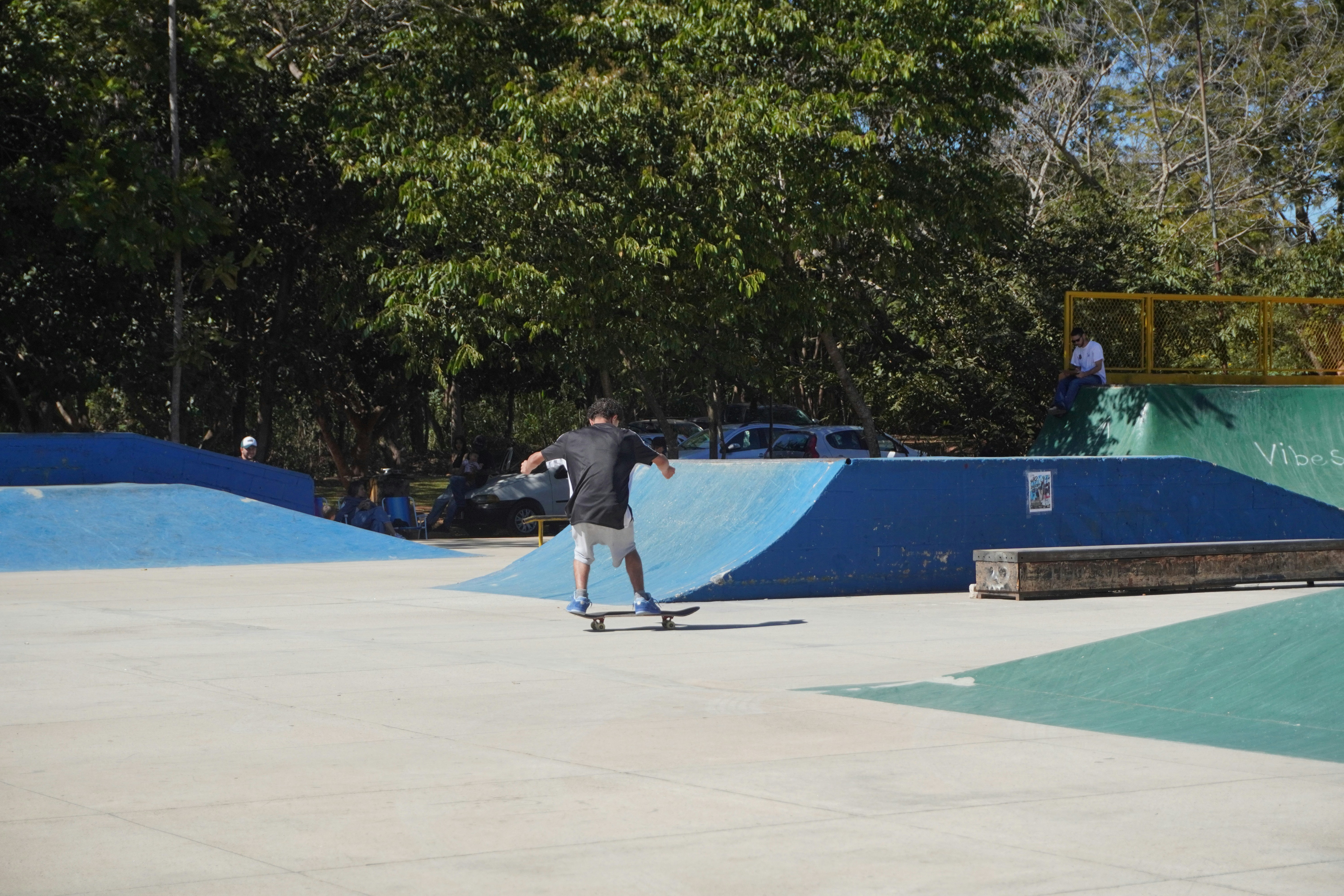 Skateboarder in mid-ride across sunlit concrete bowl