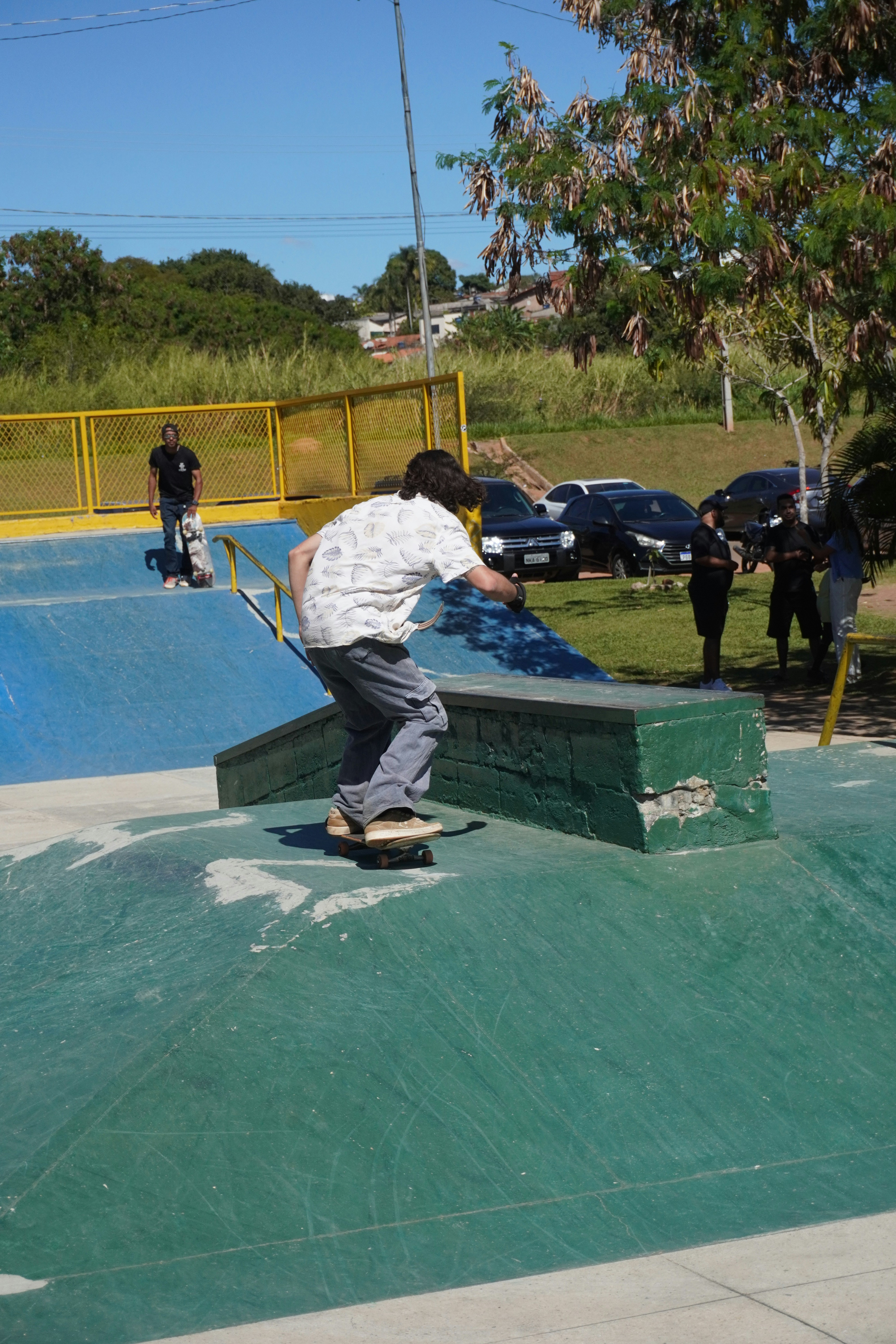 Skateboarder in mid-trick at a sunlit skatepark