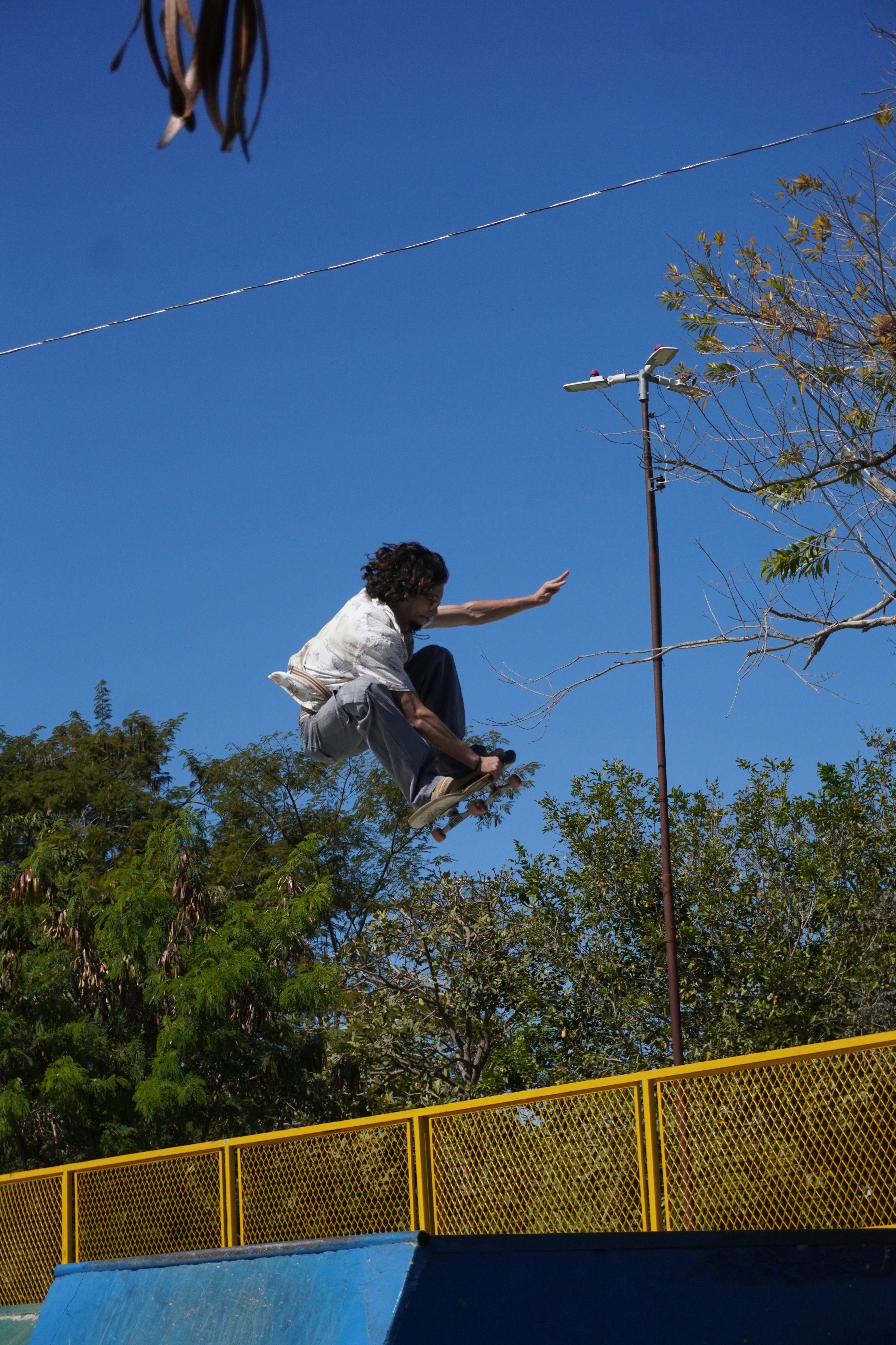 Aerial Skate—Midair Leap Over a Sunlit Fence