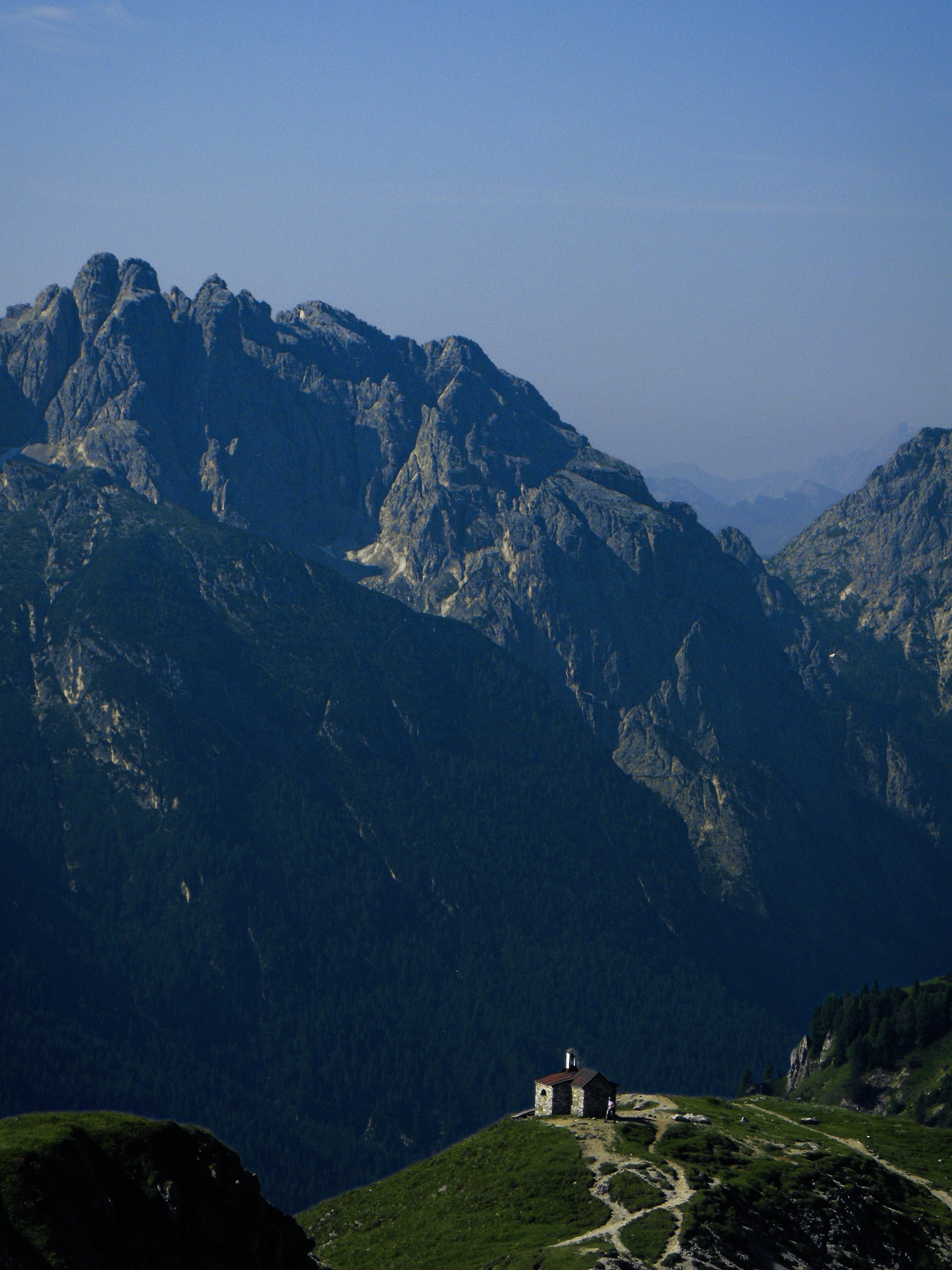 Mountain landscape with a small building on a green hill.