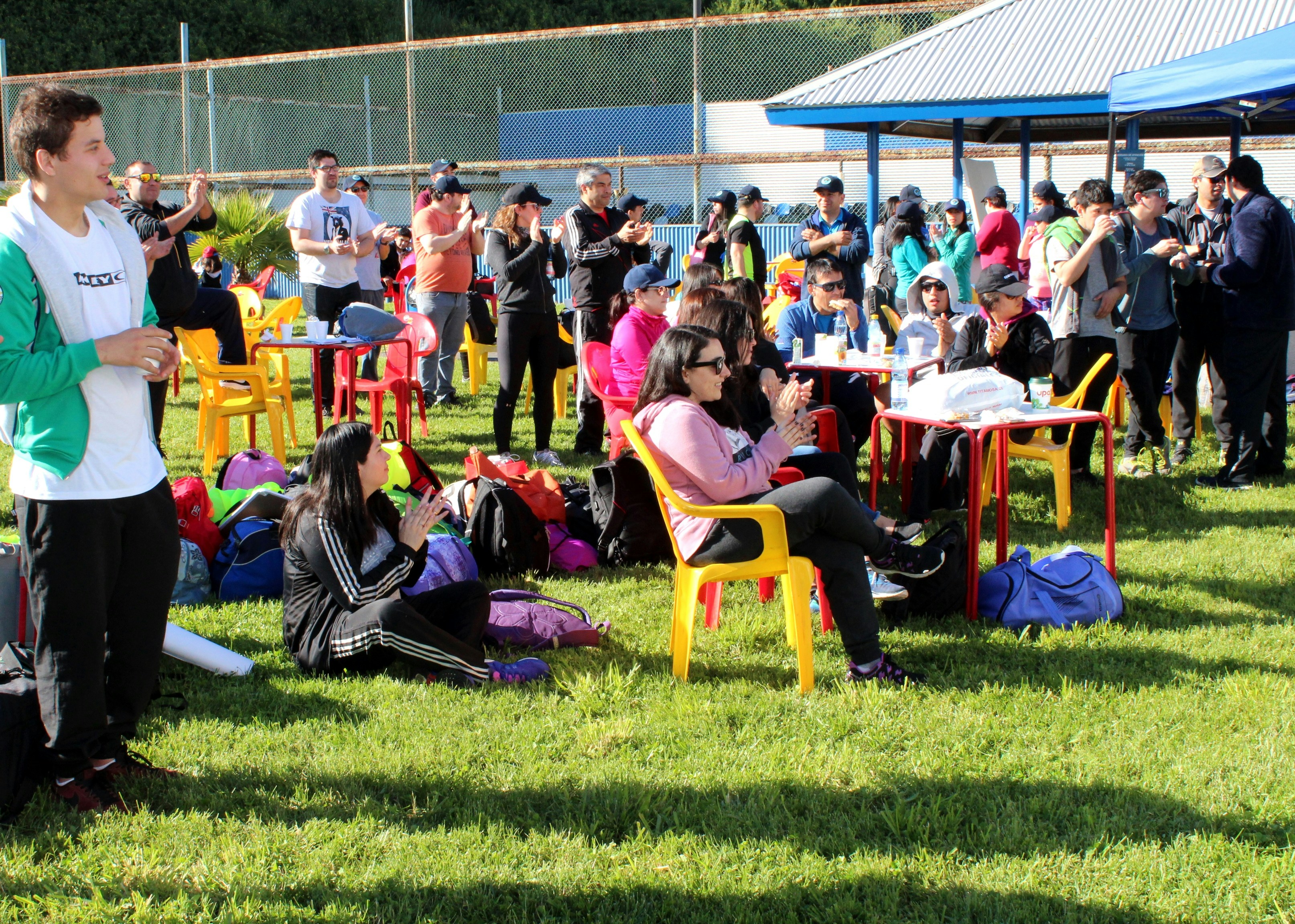 Outdoor Community Gathering: People Relaxed Around Picnic Tables Under a Covered Shelter