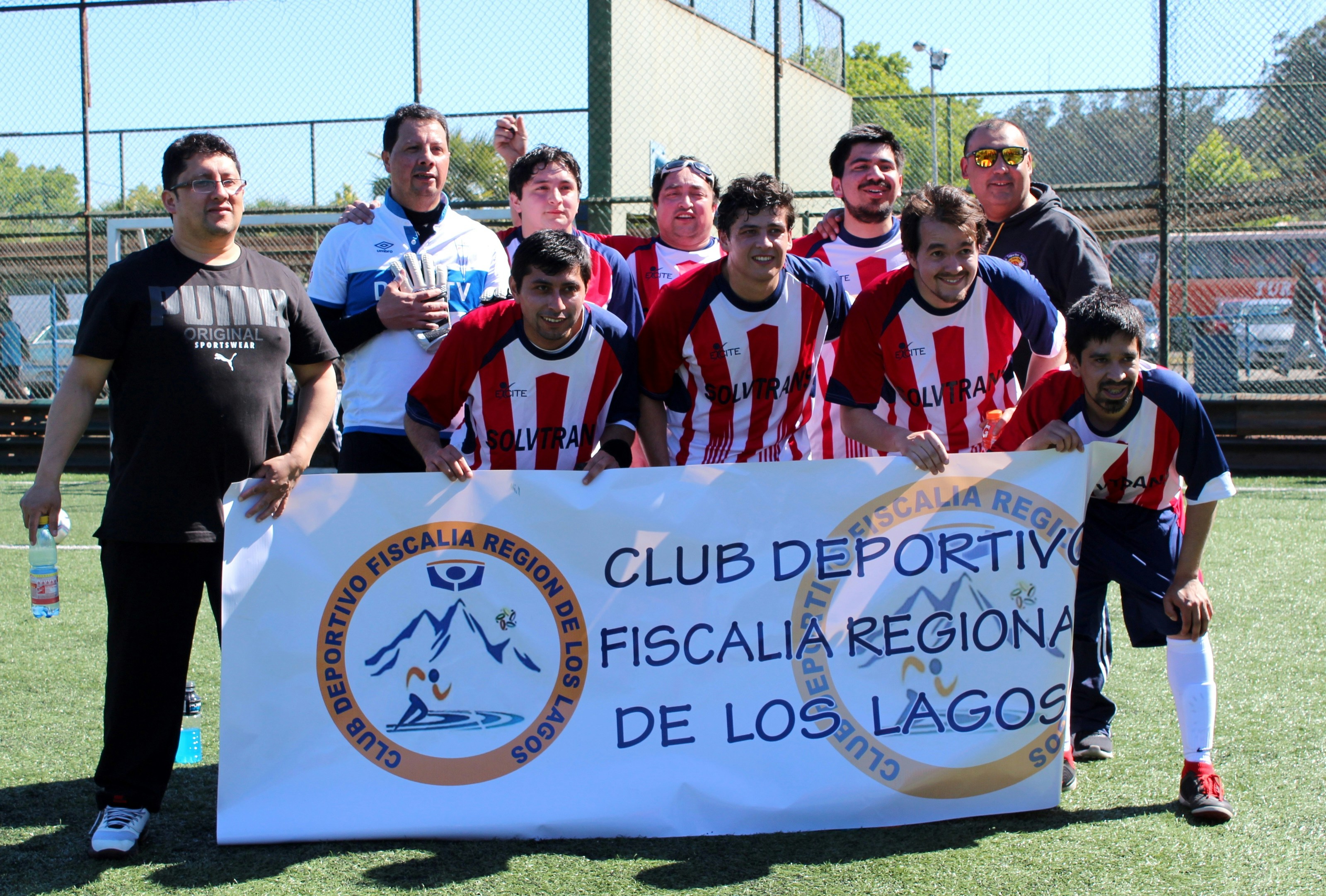 A group of men in soccer uniforms holding a banner on a sports field