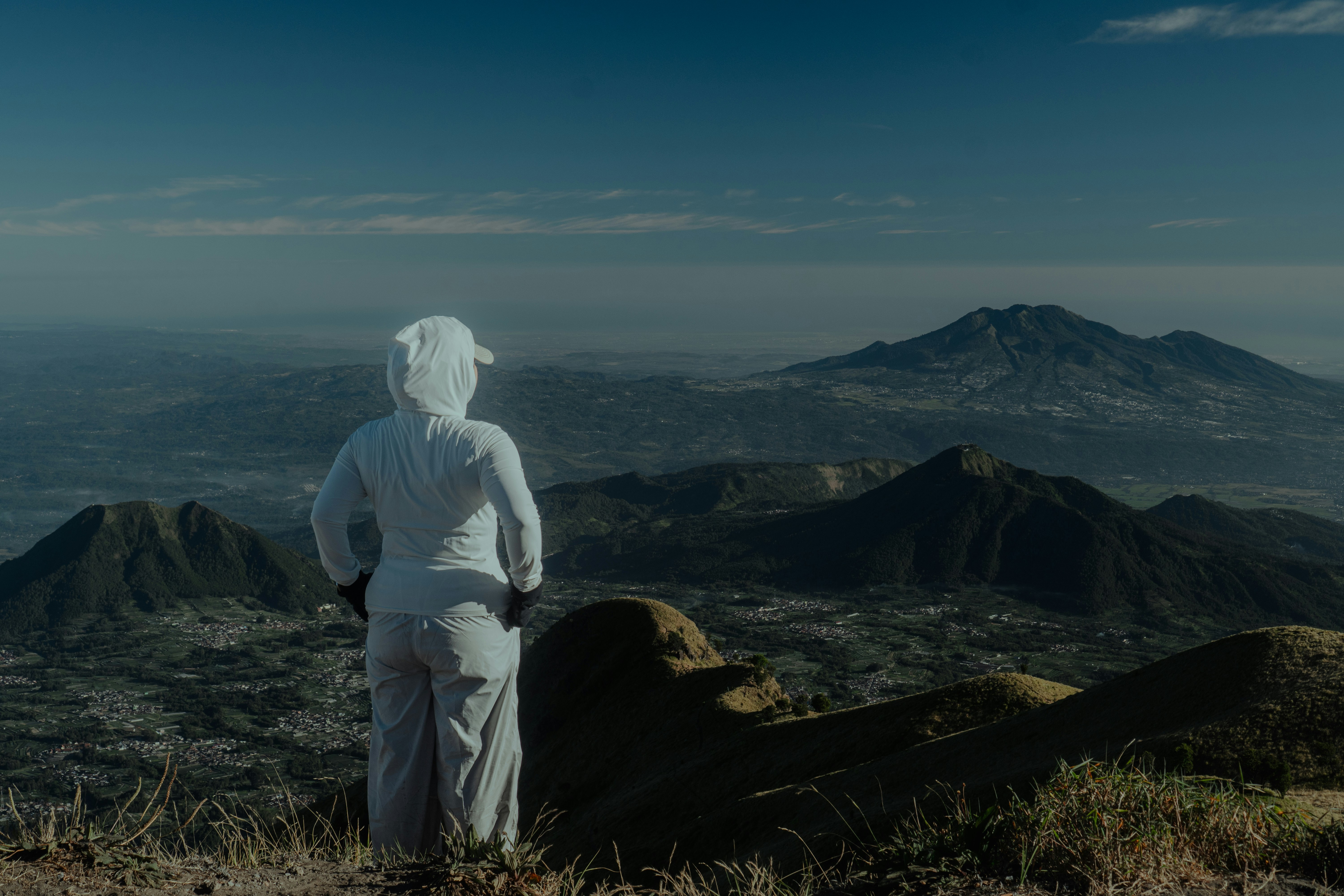 White-clad hiker gazes toward distant volcanic landscape