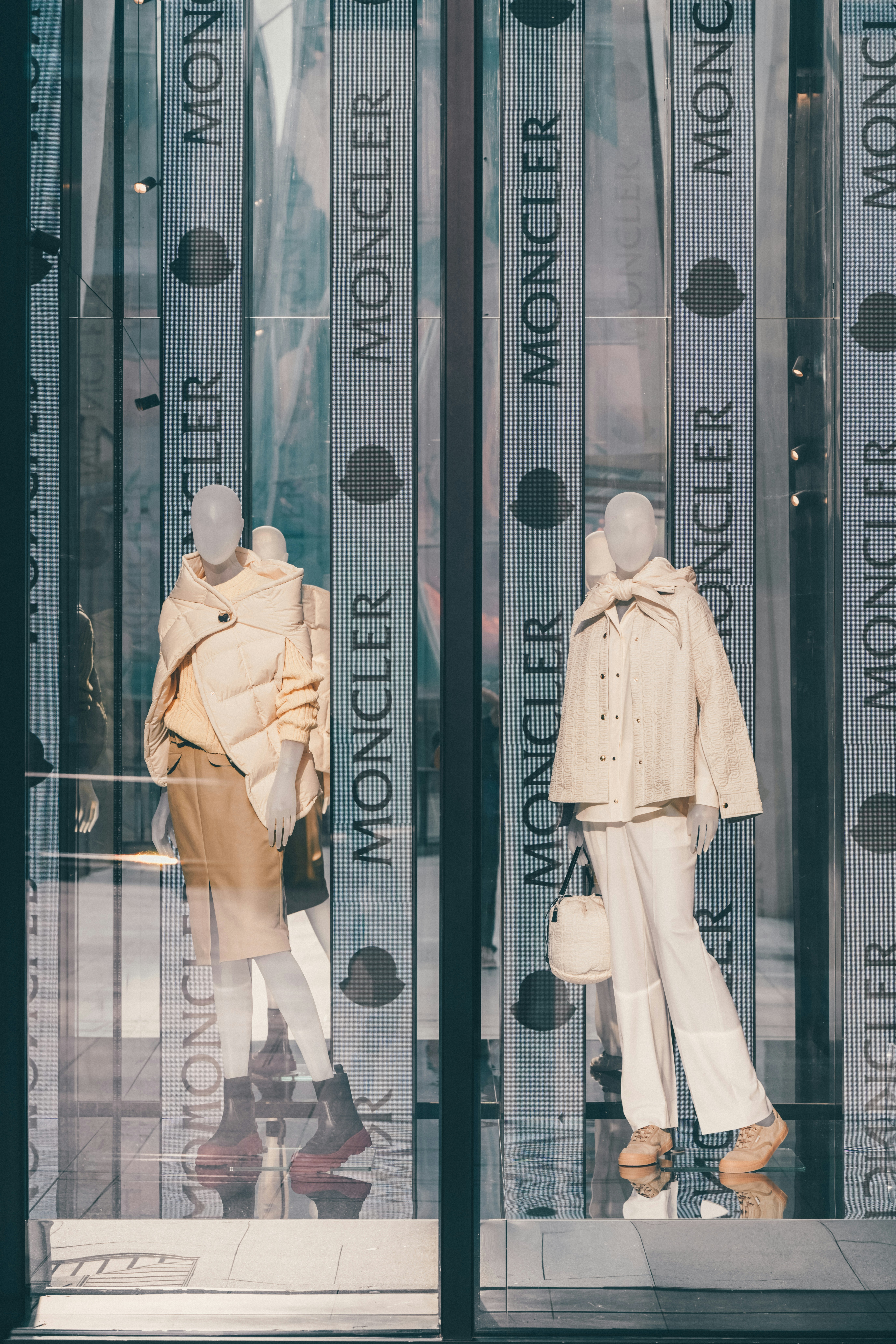 Moncler Window: Two Dressed Figures Behind Reflective Glass