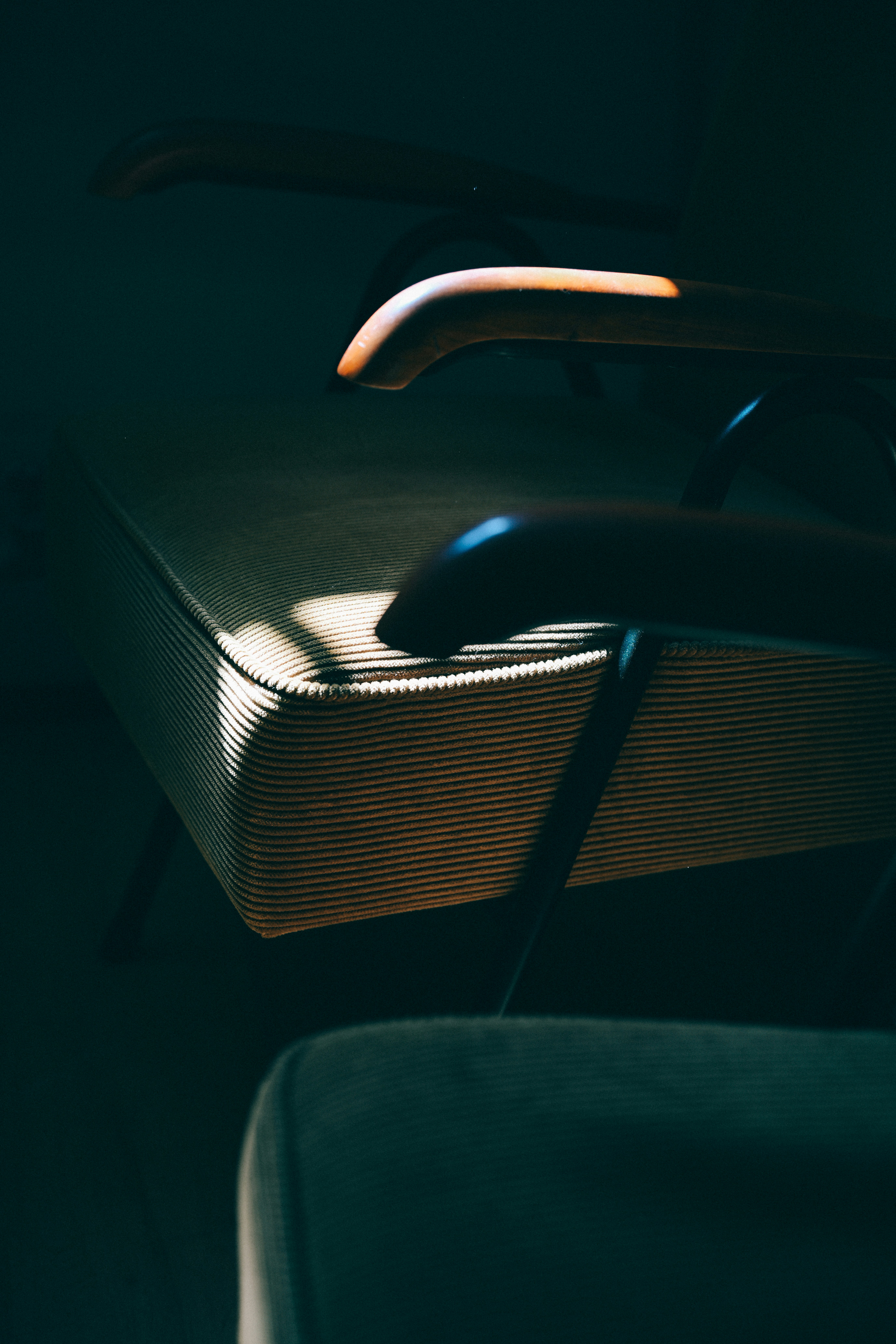 Low-Light Studio Chair: Textured Fabric and Curved Armrests in Shadow