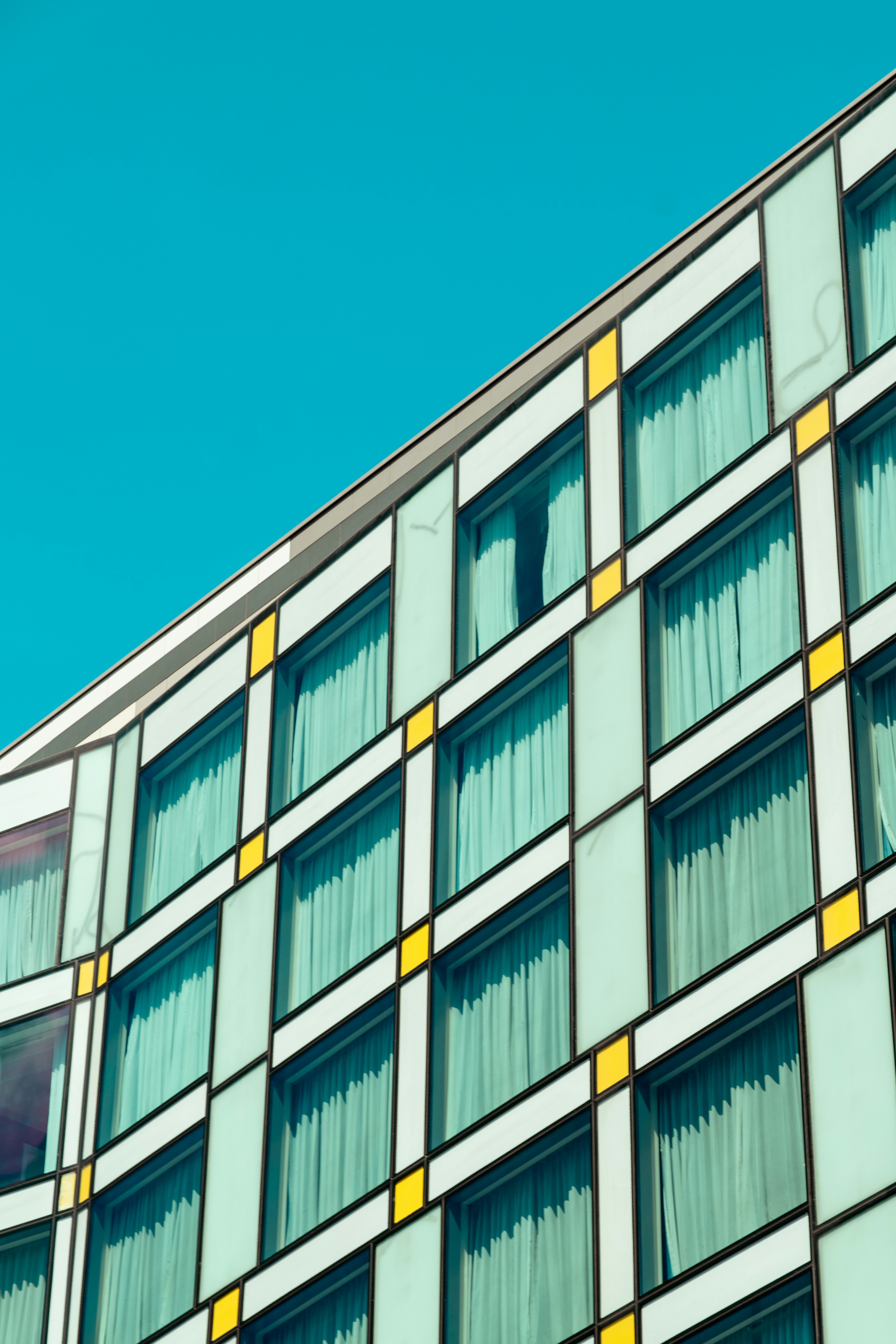 Diagonal Grid in Turquoise: A Modern Facade with Yellow Accents