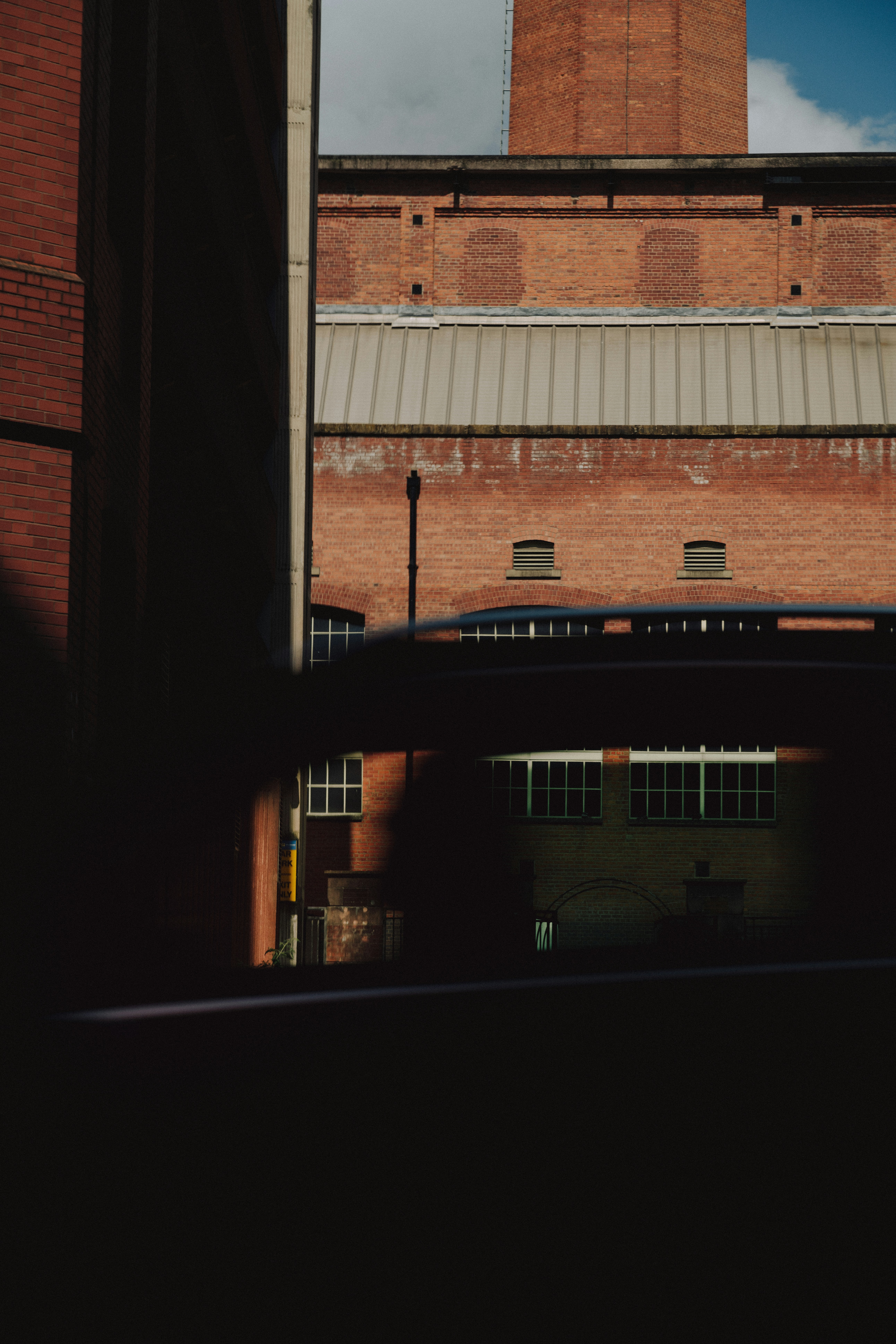 Brickwork Shadowplay: A Narrow Alley Between Industrial Facades