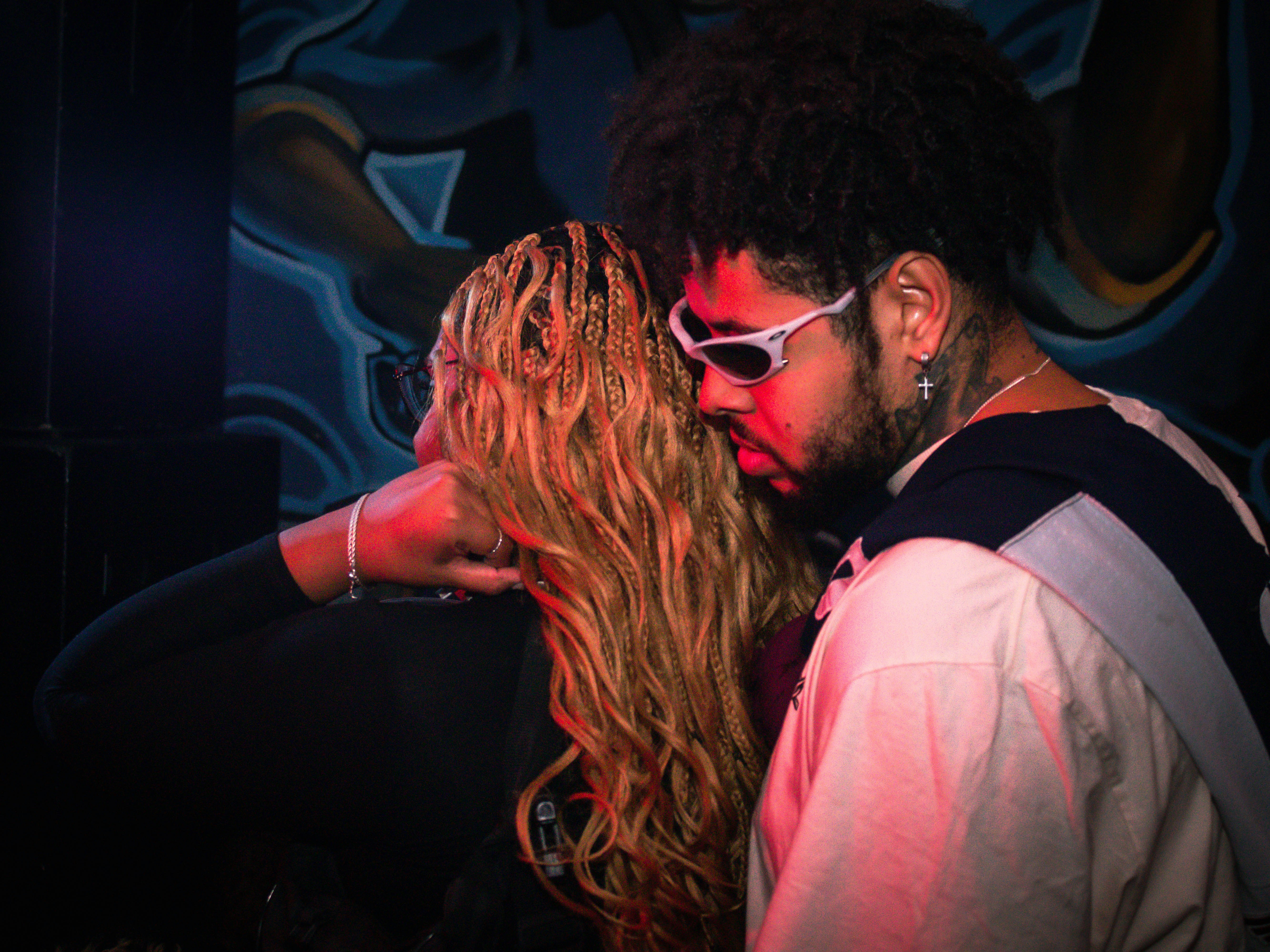 Neon-clad duo in a shadowed club, close and contemplative