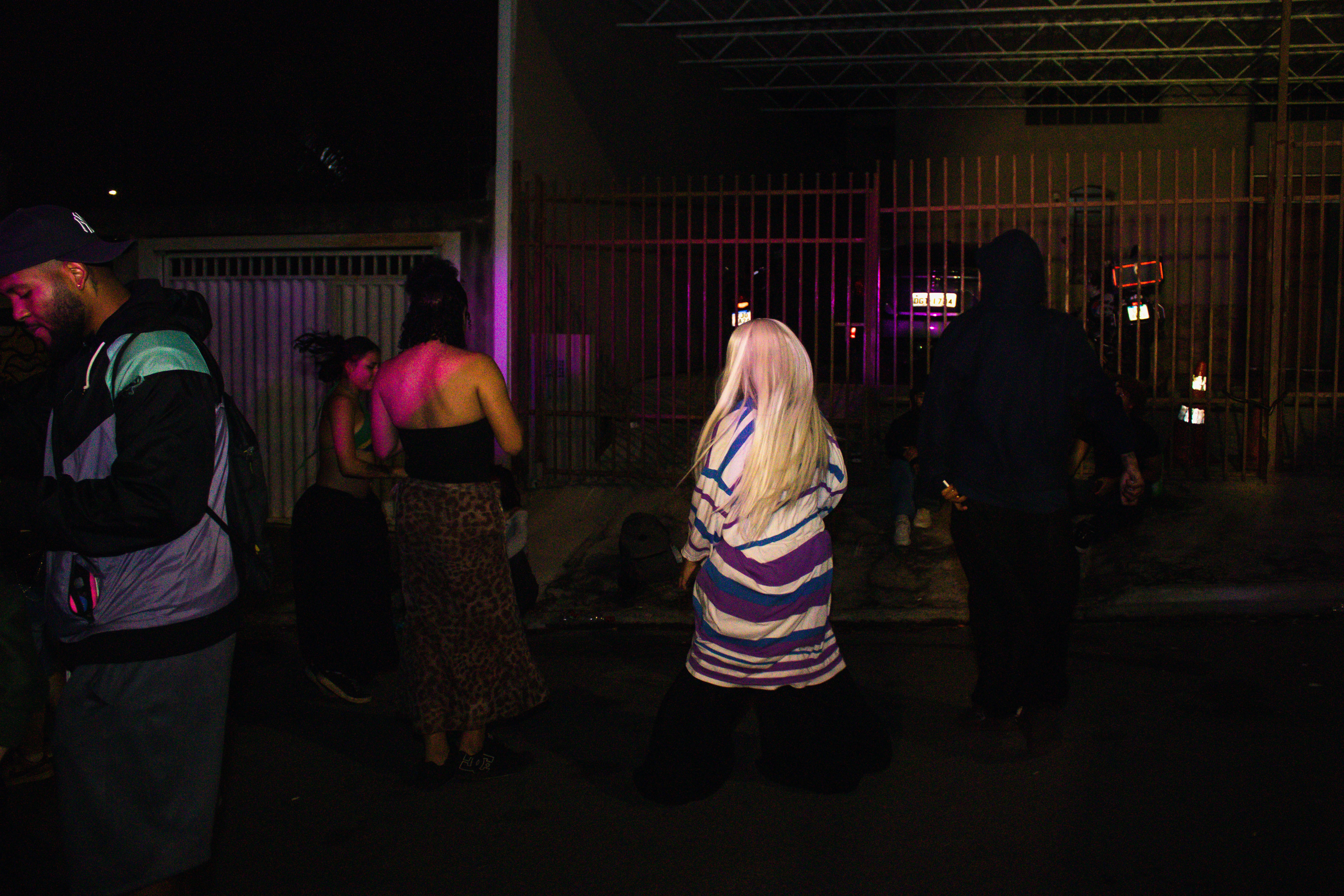 Neon Night Assembly: A Pale-Stranded Figure in a Row of Quiet Dancers