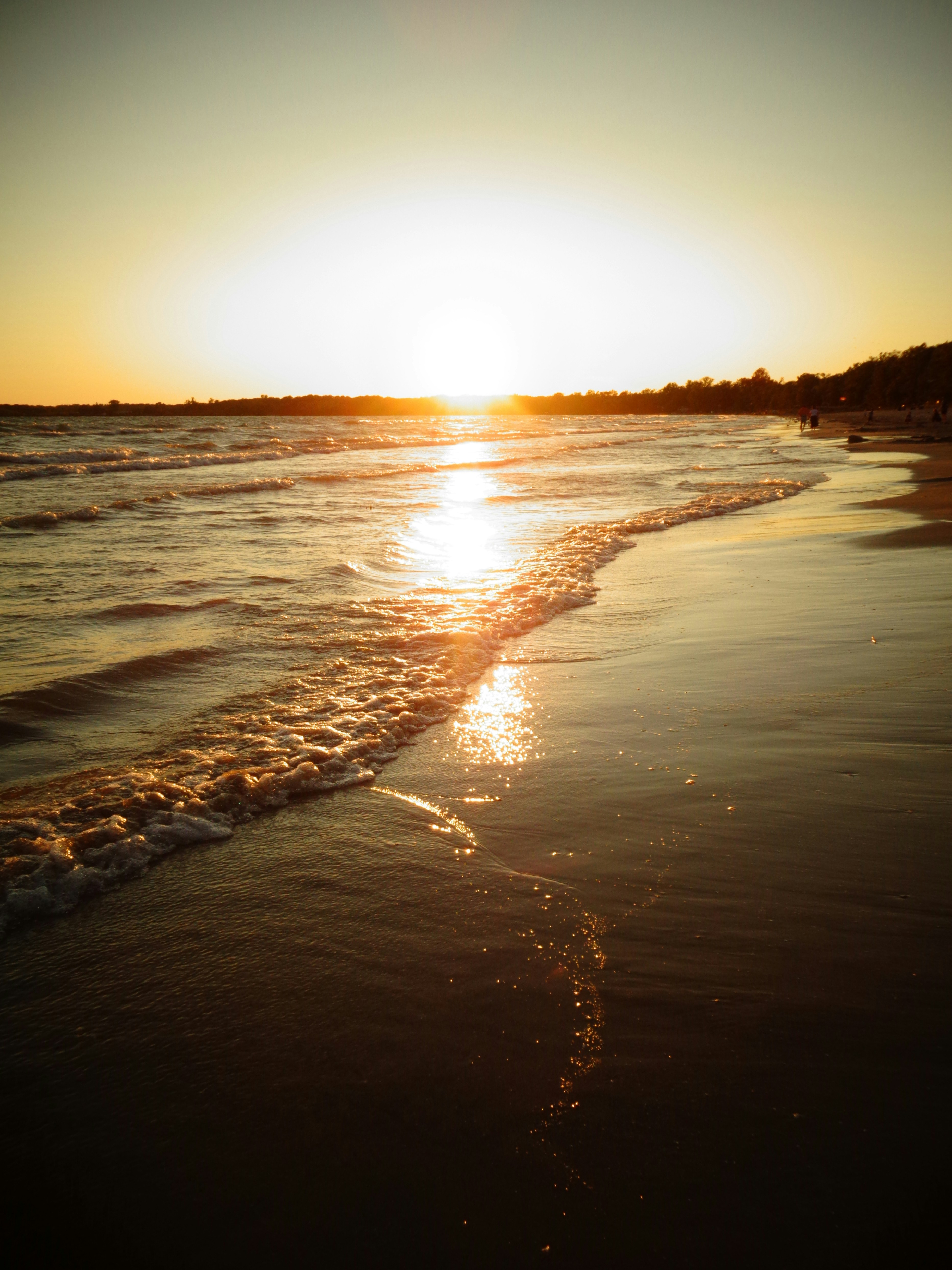 Sunlit shoreline: calm waves kiss a golden horizon at dusk