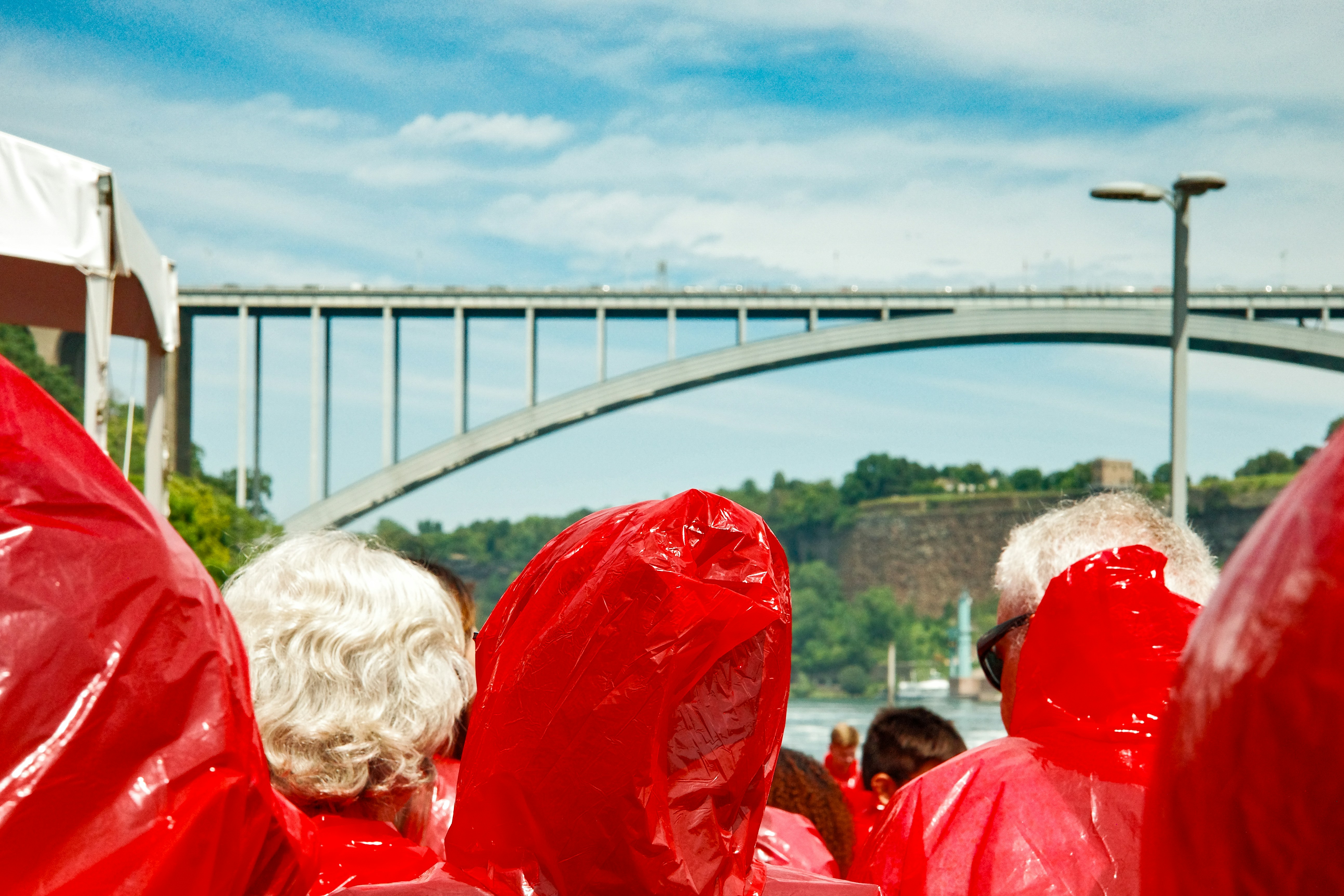 Red Hooded Crowd at a City Riverfront Event Under a Bridge