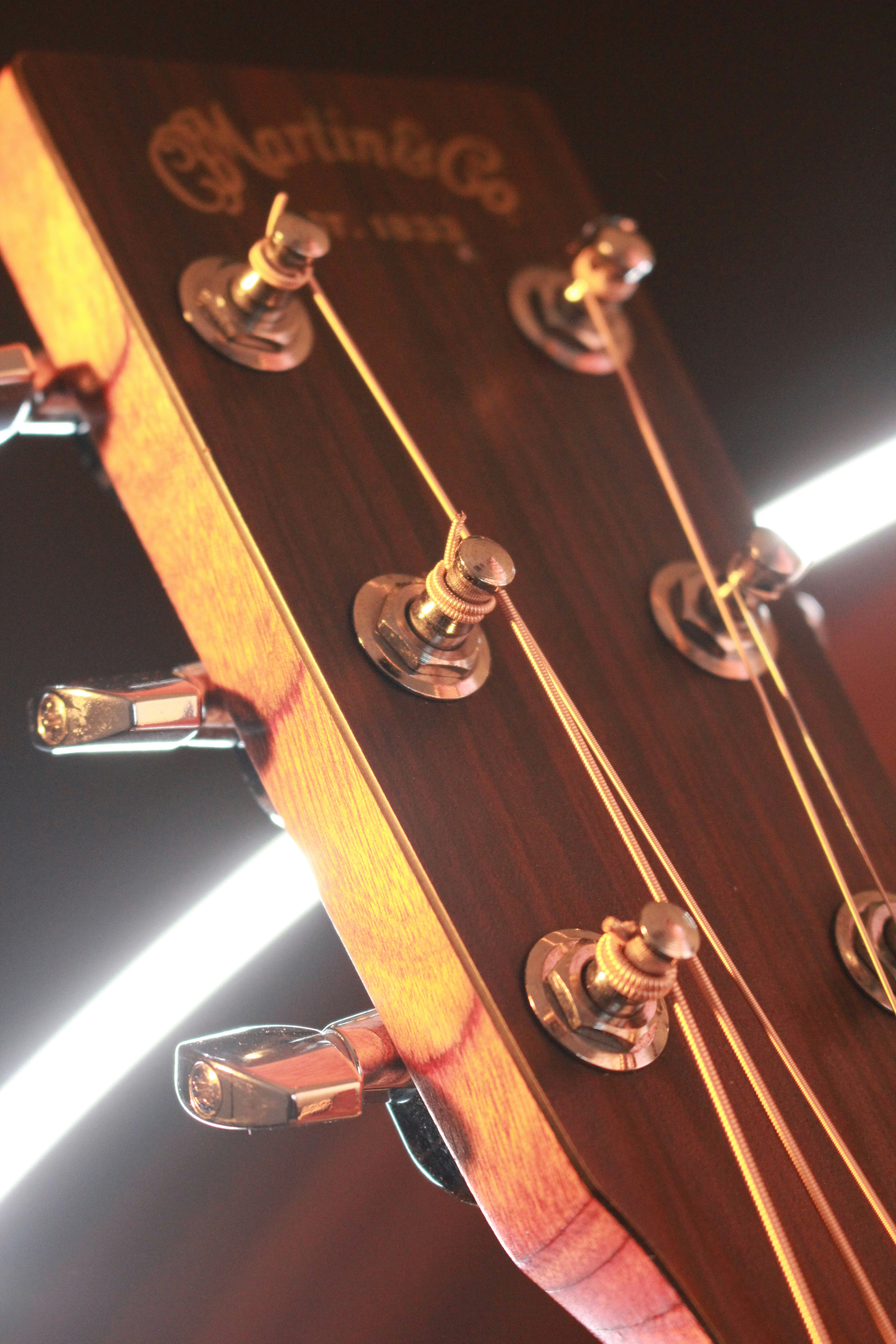 Guitar Headstock Close-Up: Warm Wood, Steel Strings and a Neon Glow
