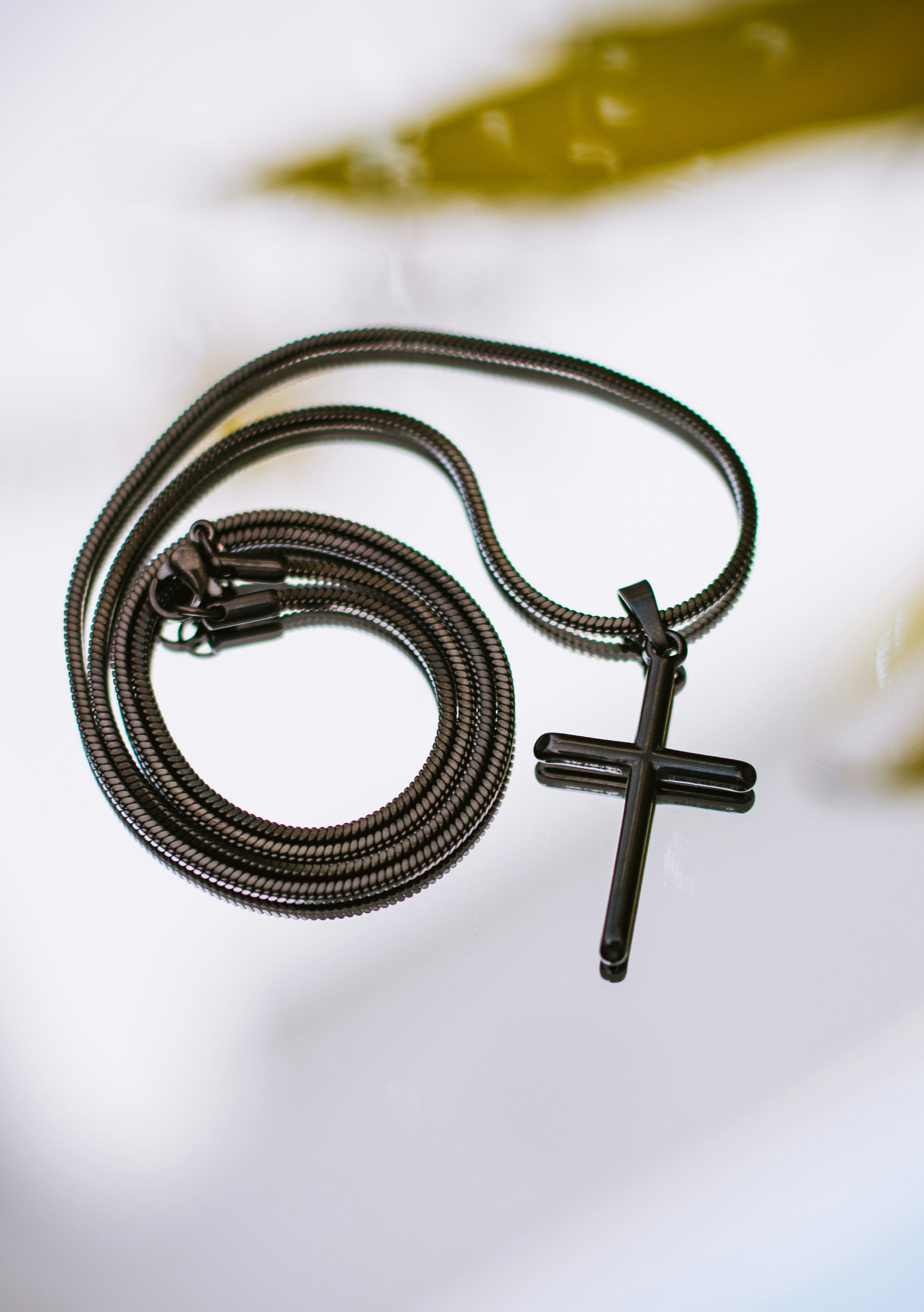 Dark Cross Pendant on Coiled Cord: A Still Life of Contrast and Craft