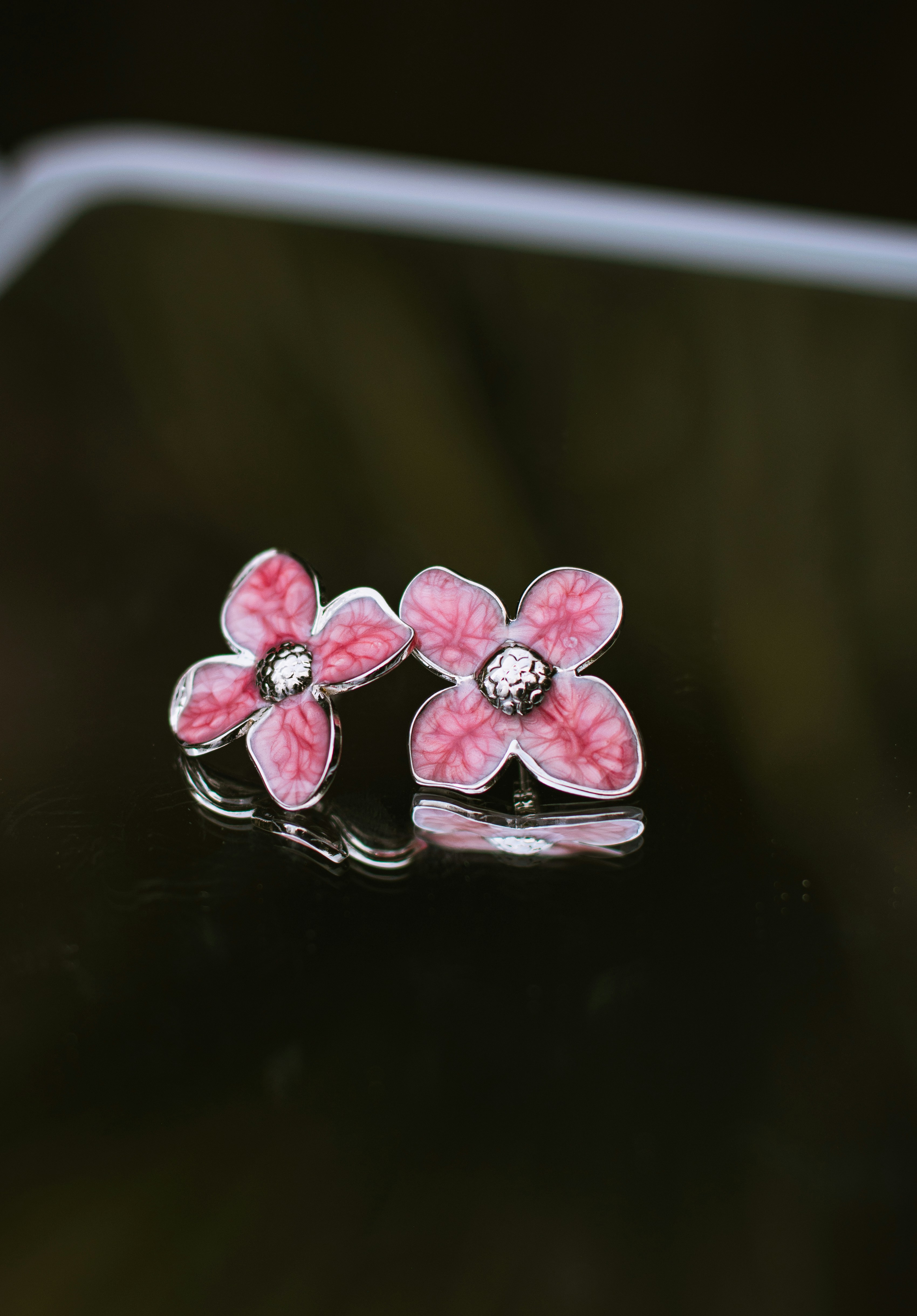 Petal Pair: Pink Flowered Cufflinks Resting on a Reflective Surface