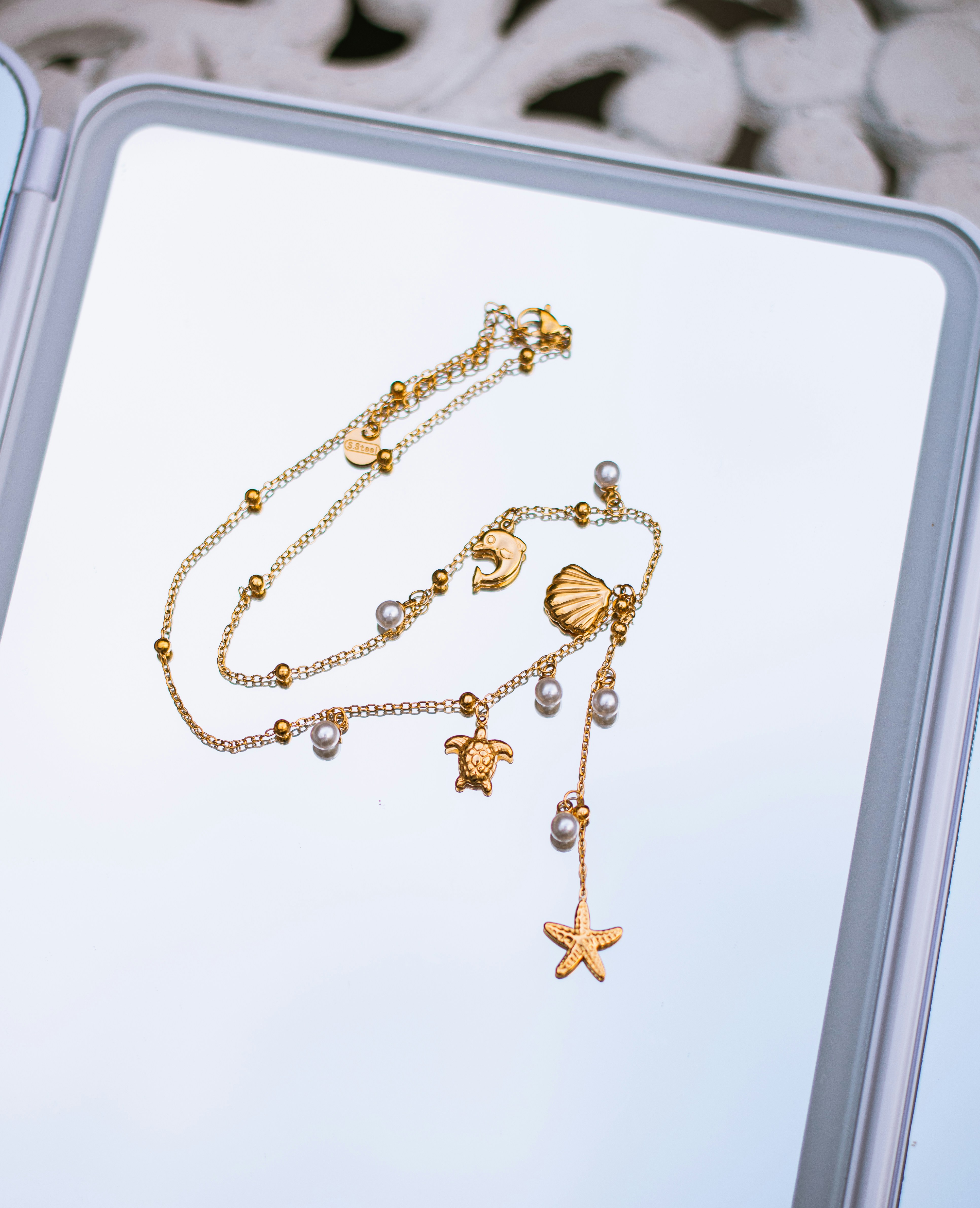 Gold Harbor: Jewelry Necklace Cascades Across a Mirror