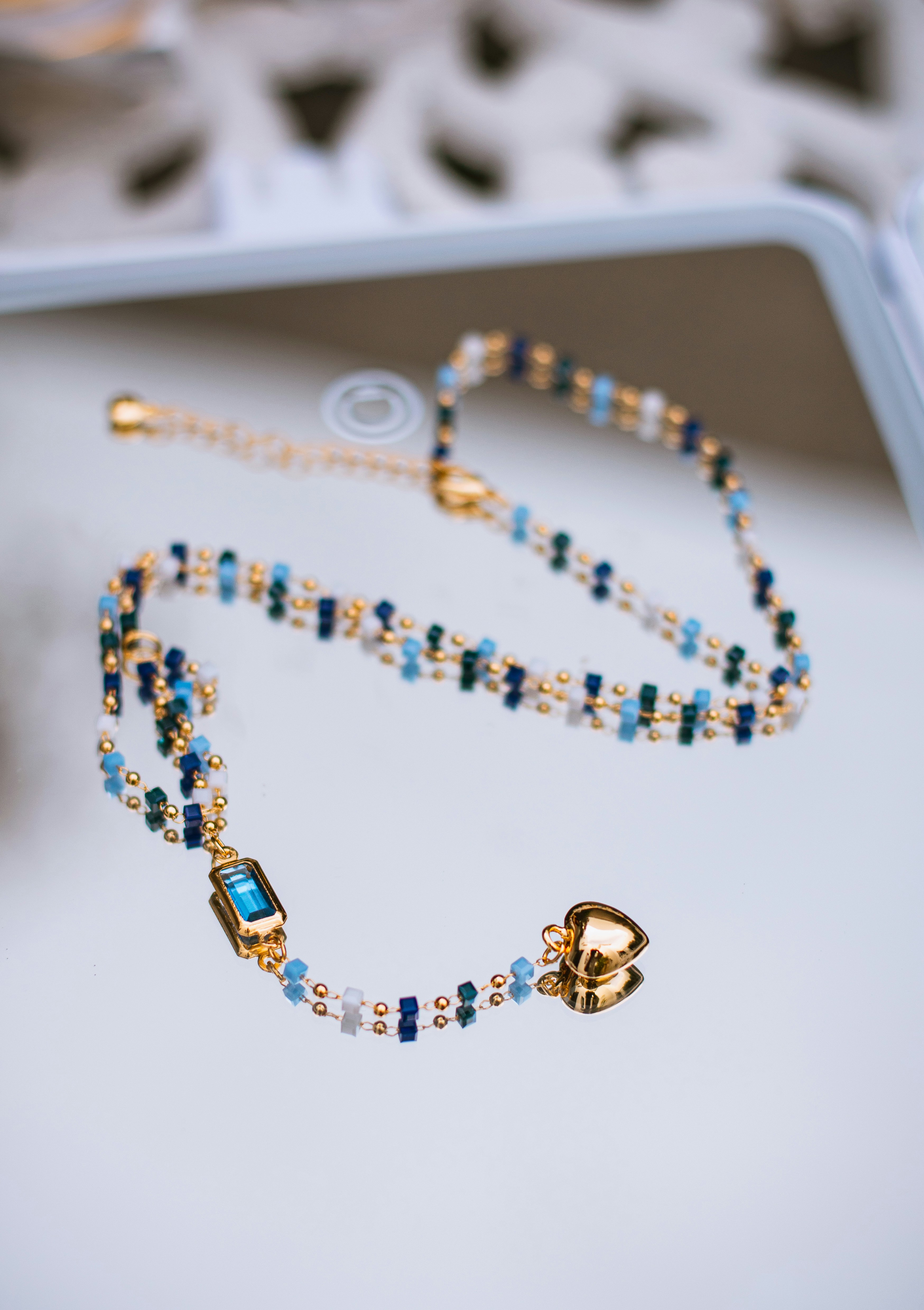 Blue-Gold Gem Necklace Silhouette on a Reflective Surface