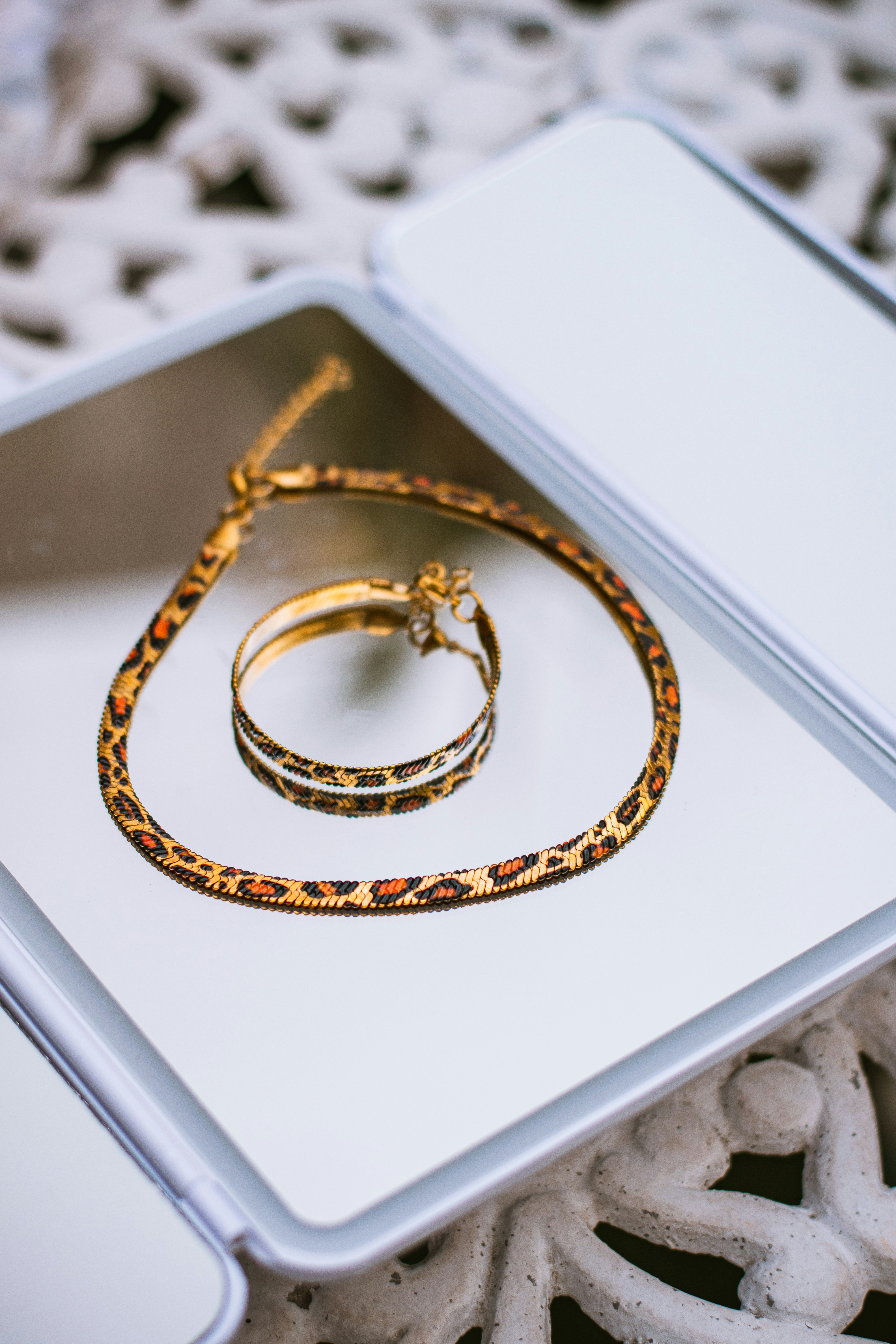 Gold-and-Black Coil: Jewelry Resting on a Mirror Within a Box