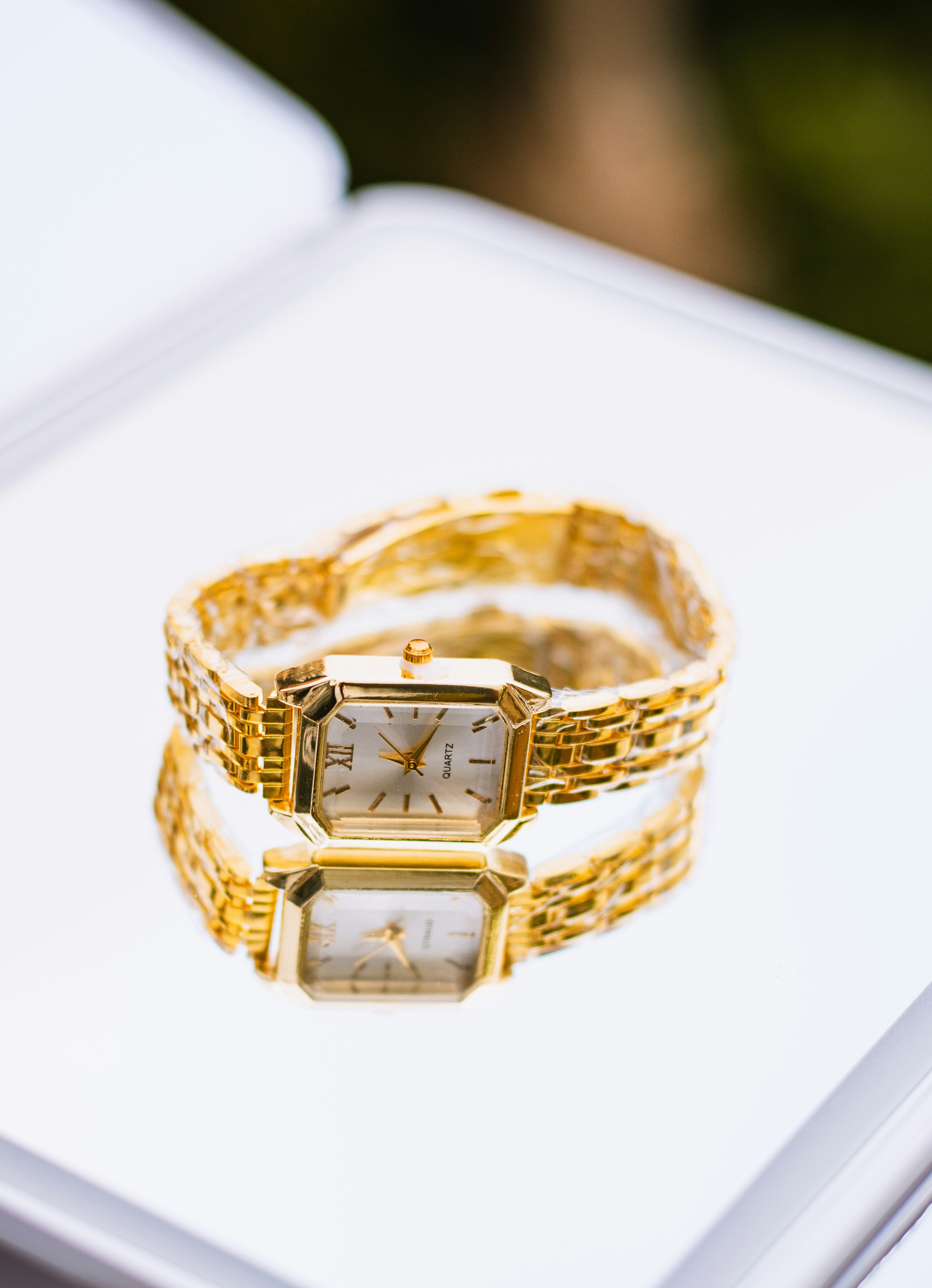 Golden Timekeeper: A Luxe Wristwatch Resting on a Mirrored Surface