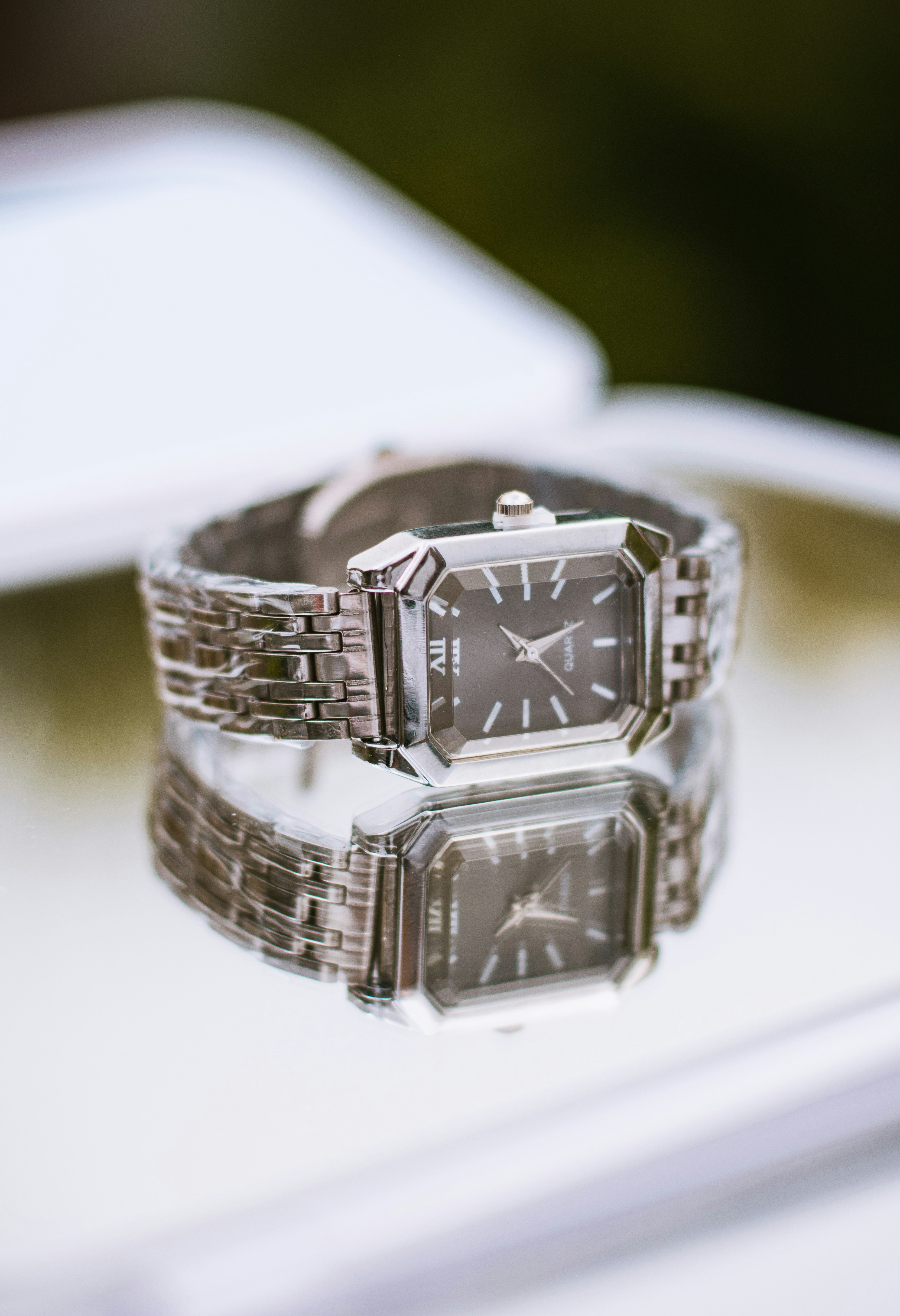 Mirror-Tone: A Silver Wristwatch Reposes on a Gleaming Surface