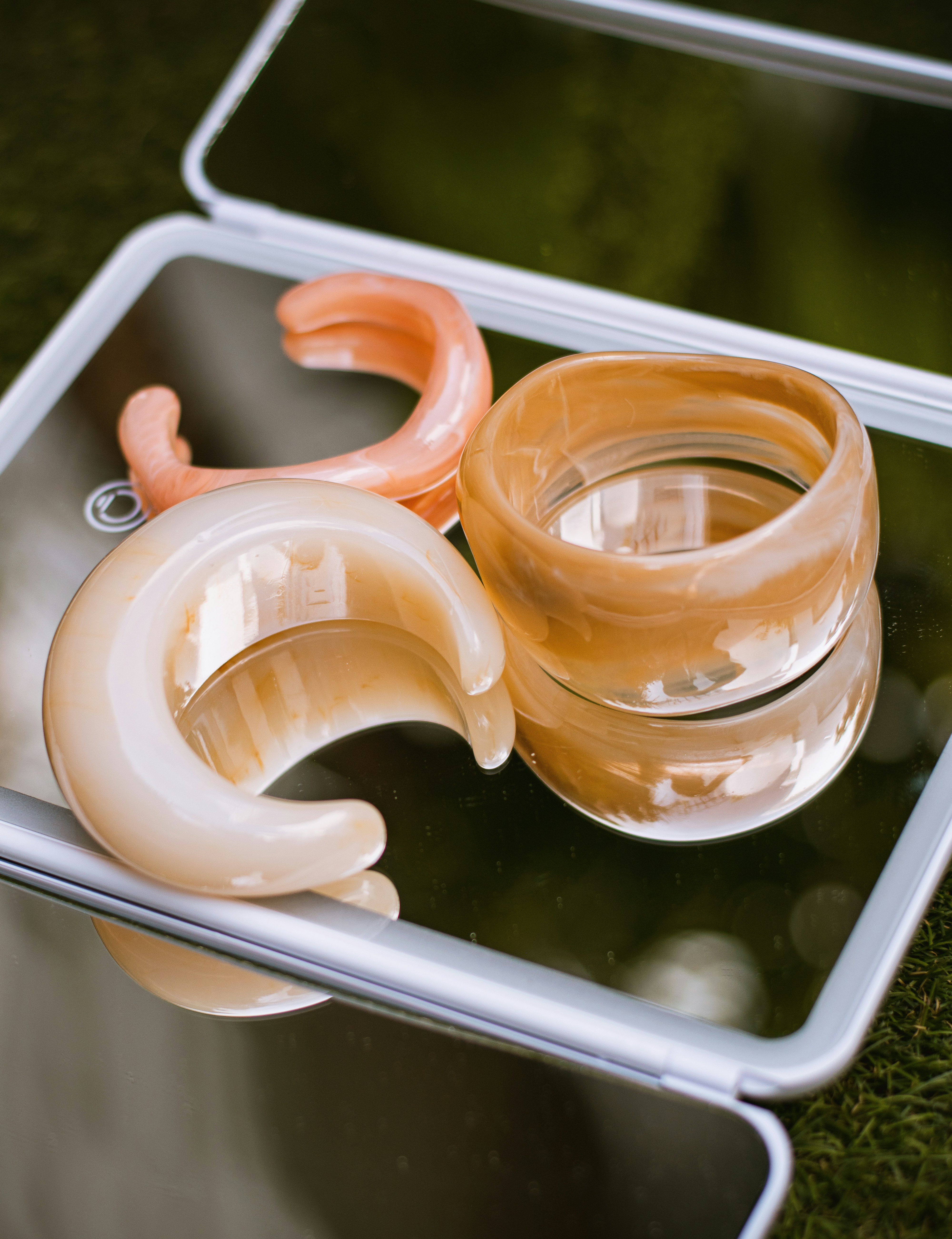 Clear dental aligners arranged on a mirrored tray, reflecting softly in the surface for a minimal, clinical still life.