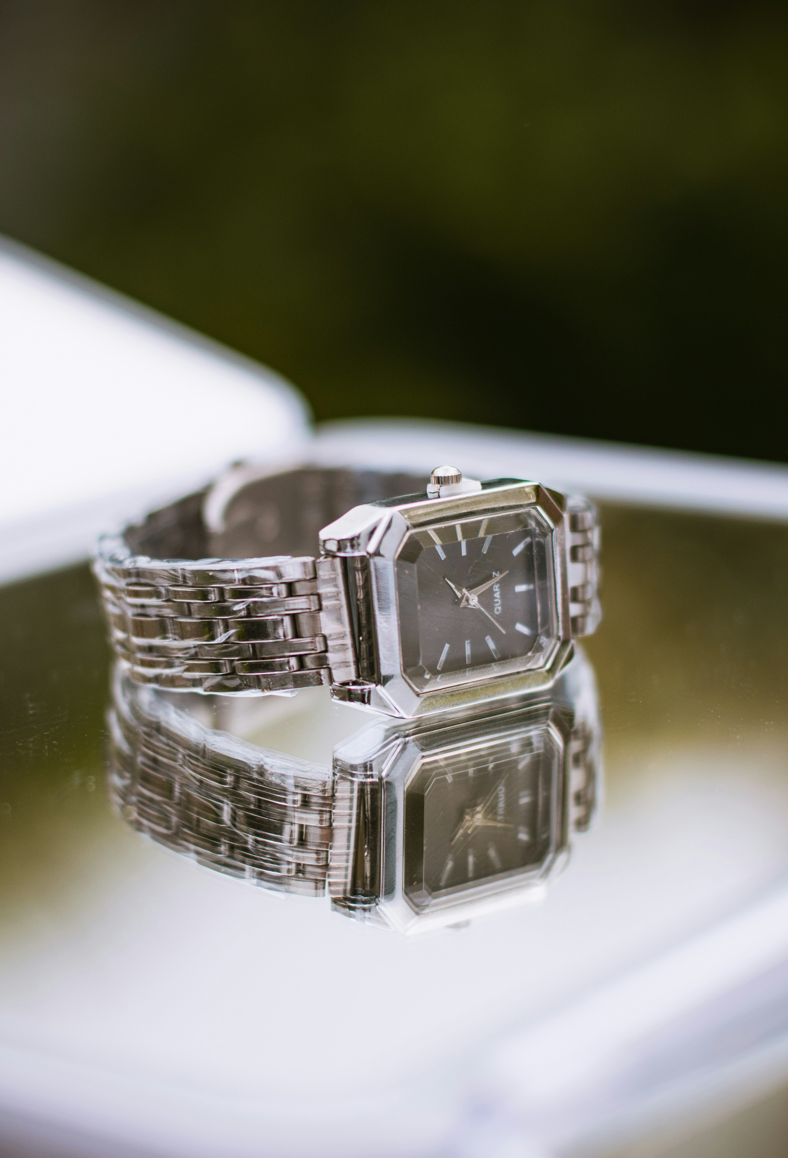 Reflected Precision: a stainless-steel wristwatch resting on a mirrored surface