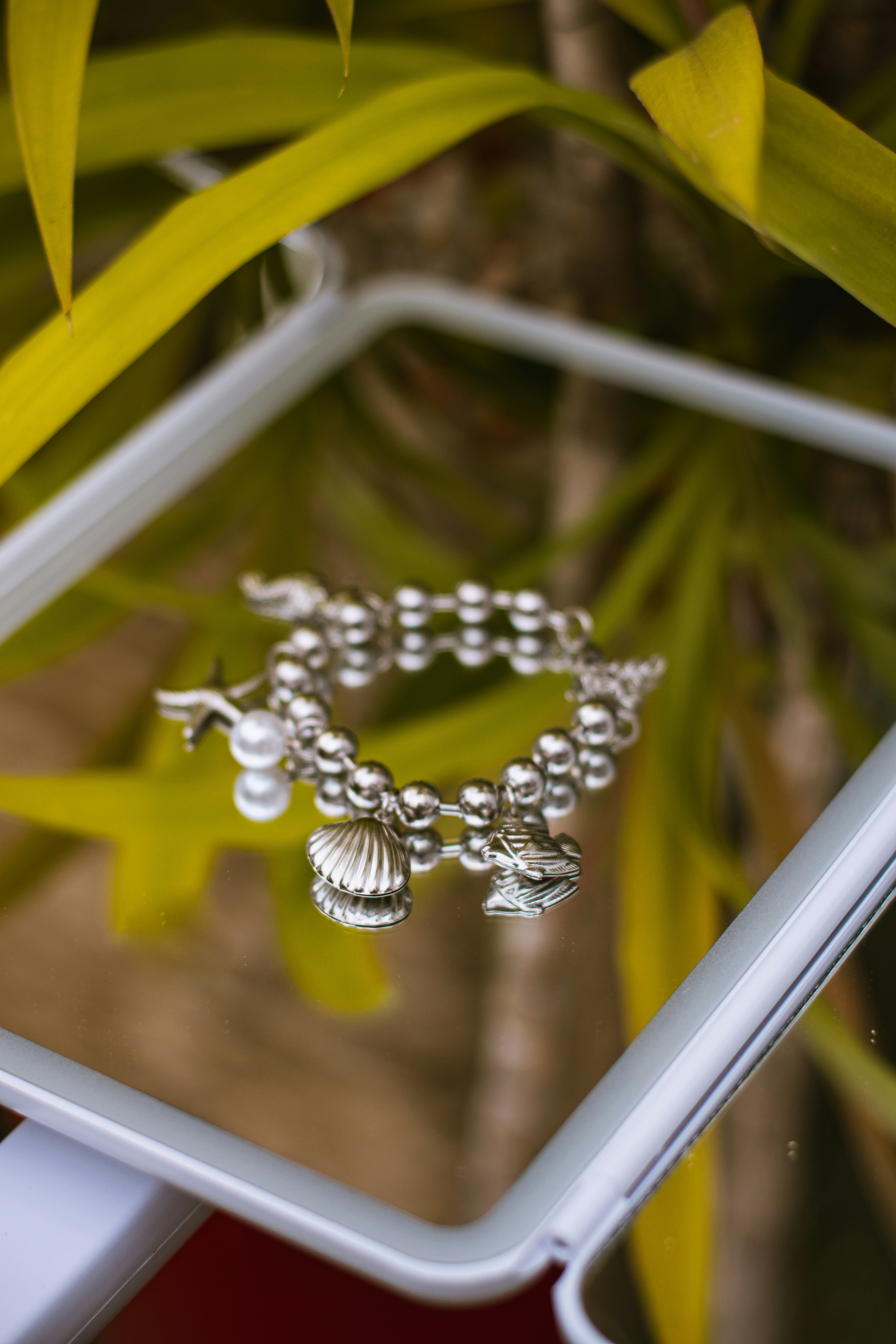 Floating charm: a silver bracelet mirrors a glass surface for a delicate automotive of shapes