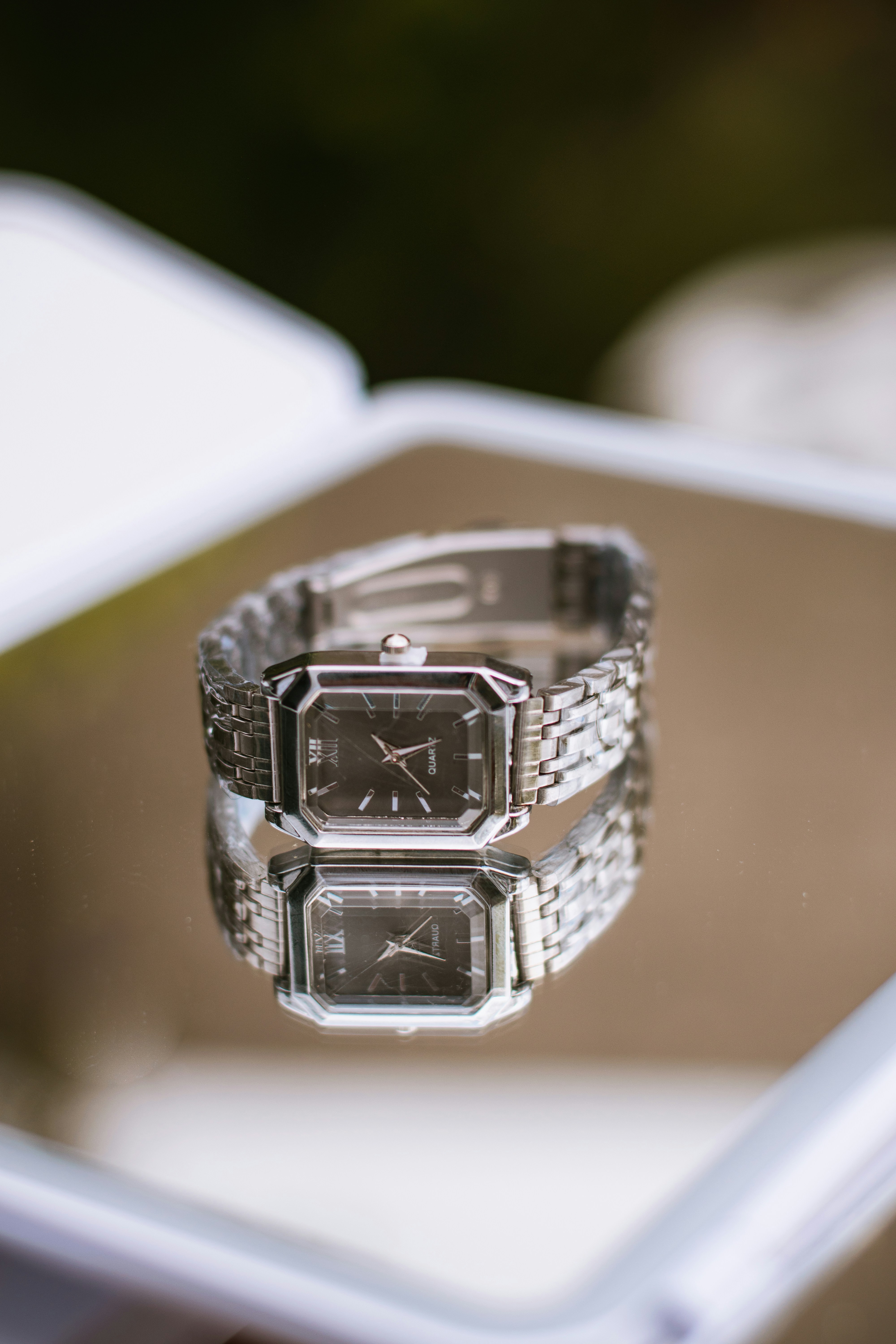Reflected Precision: A Stainless Steel Wristwatch Resting on Glass
