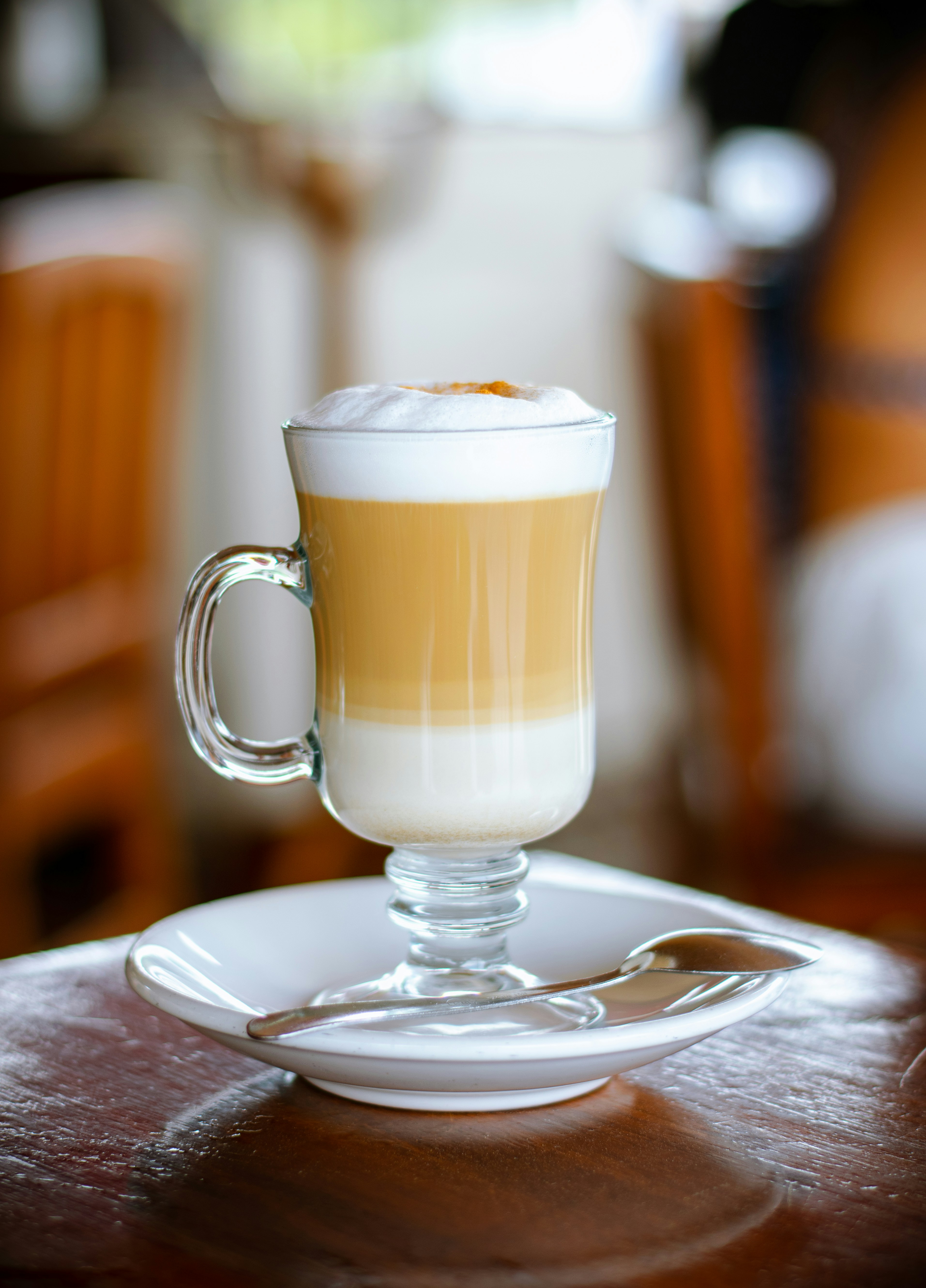 Layered latte in glass goblet: a cozy cafe portrait