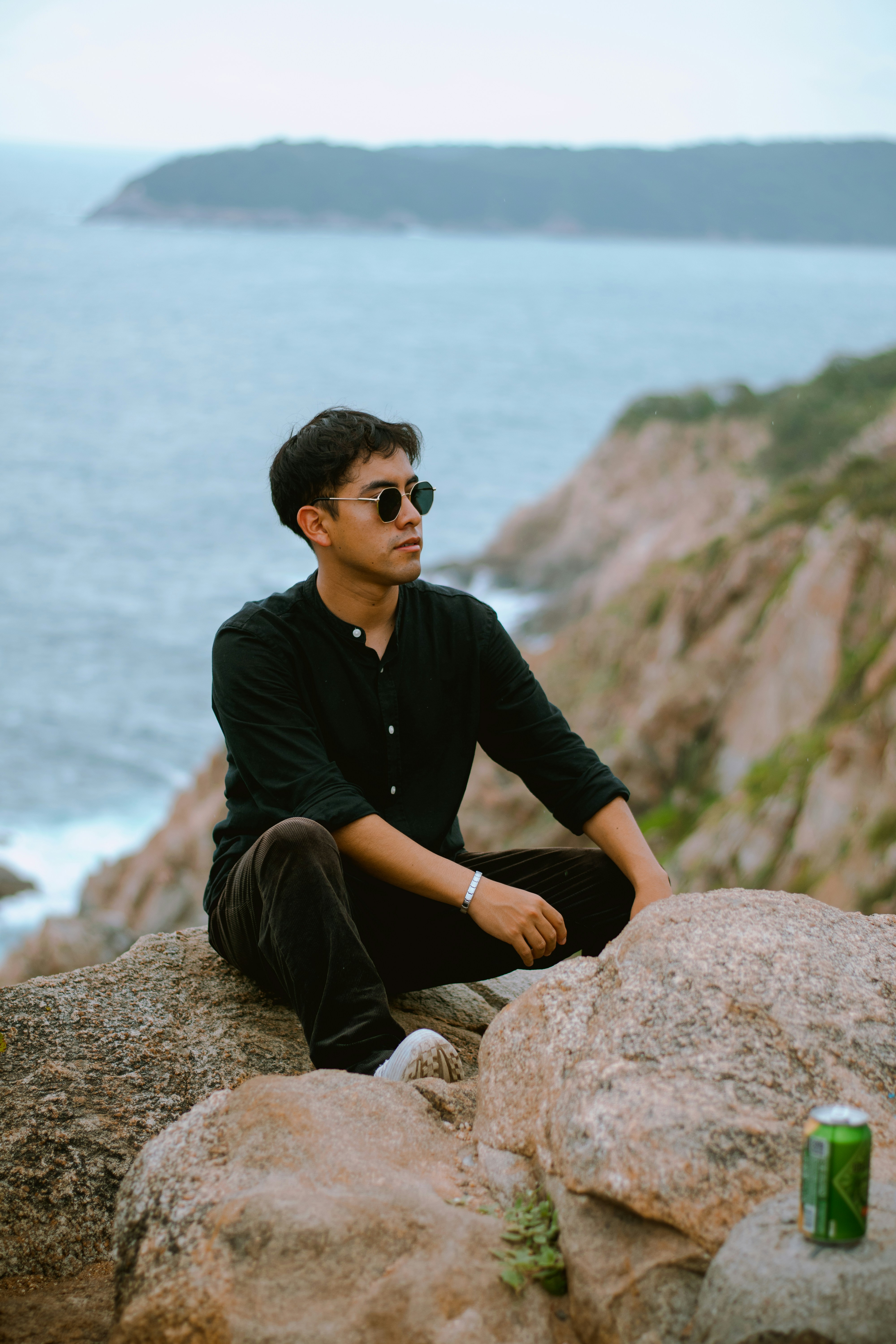 Cliffside contemplation: quiet figure in black against a coastal panorama