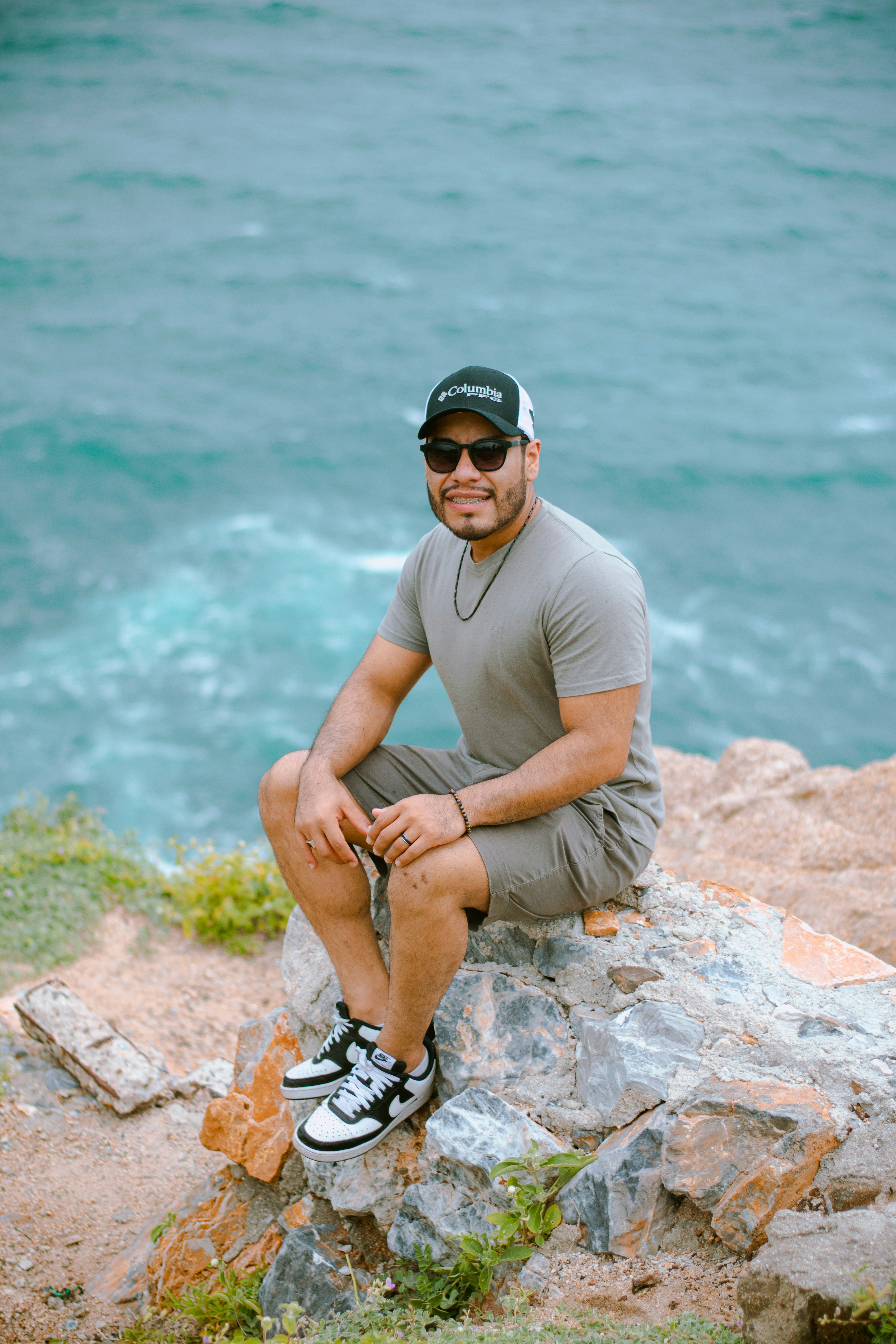 Seated on coastal rocks: a relaxed portrait with ocean backdrop