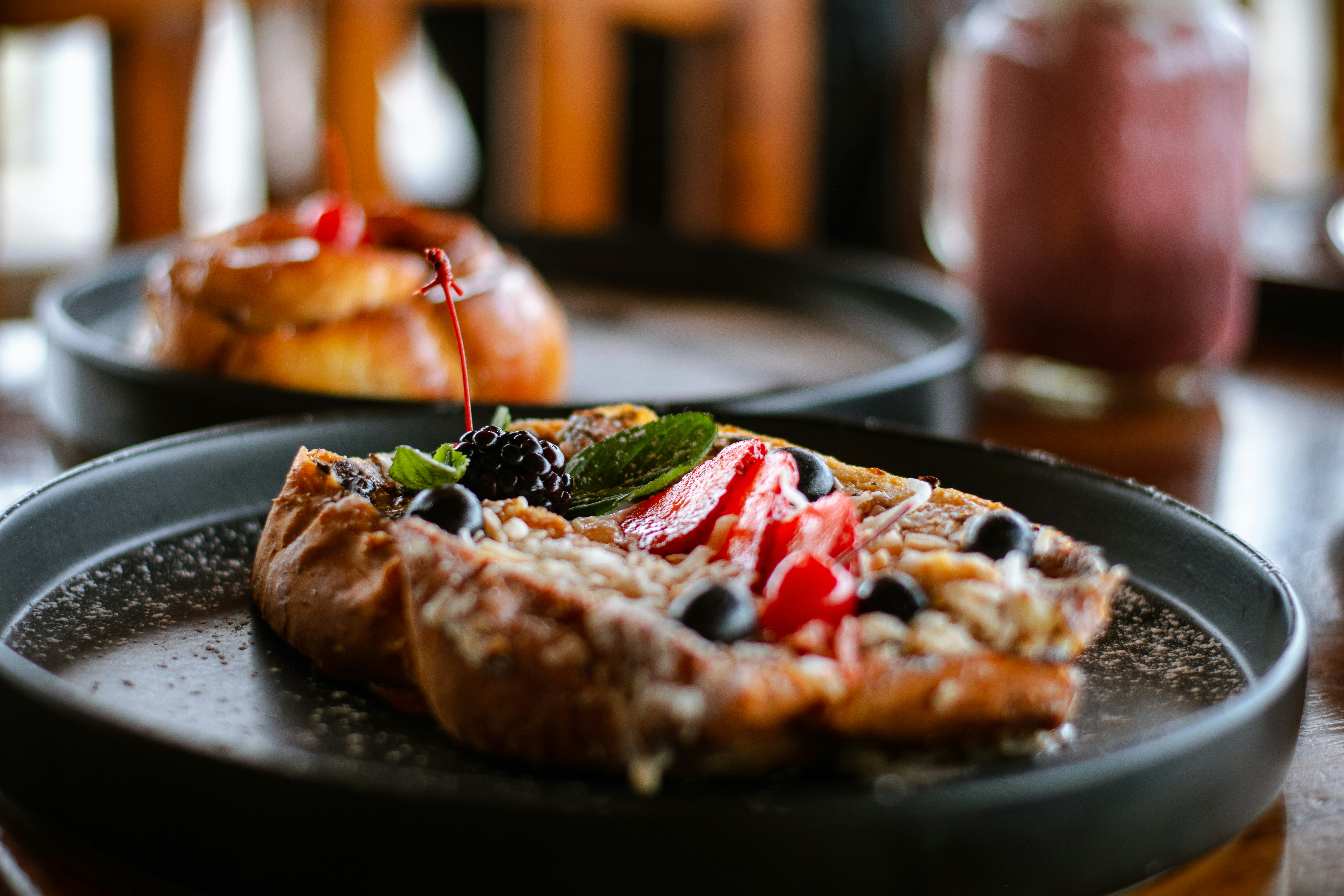 Berry-topped pastry on a glossy ceramic plate with a blurred indulgence in the background