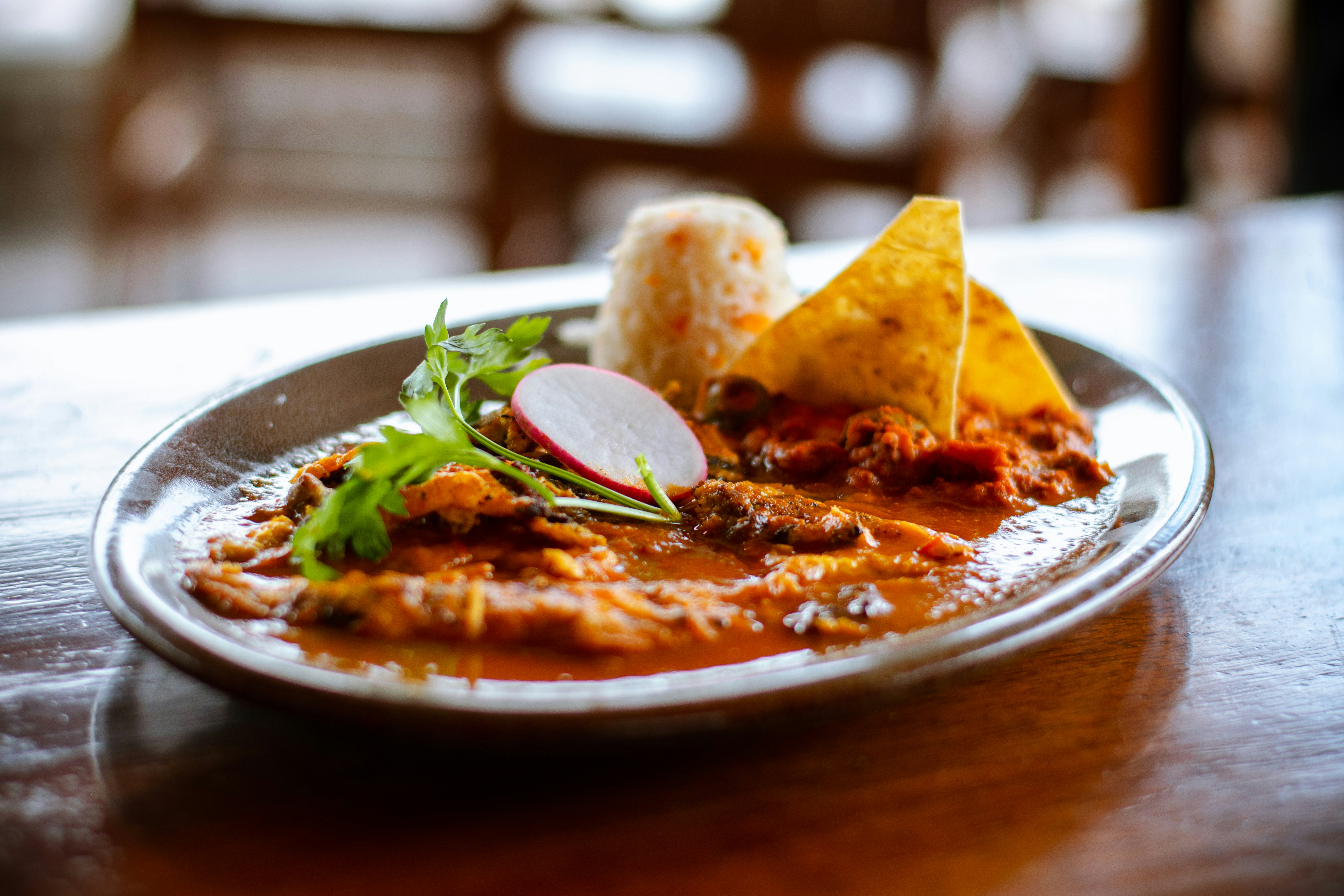Savory Tex-Malsaínto: A Chip-Topped Cocoa Red Stew with Fresh Garnish