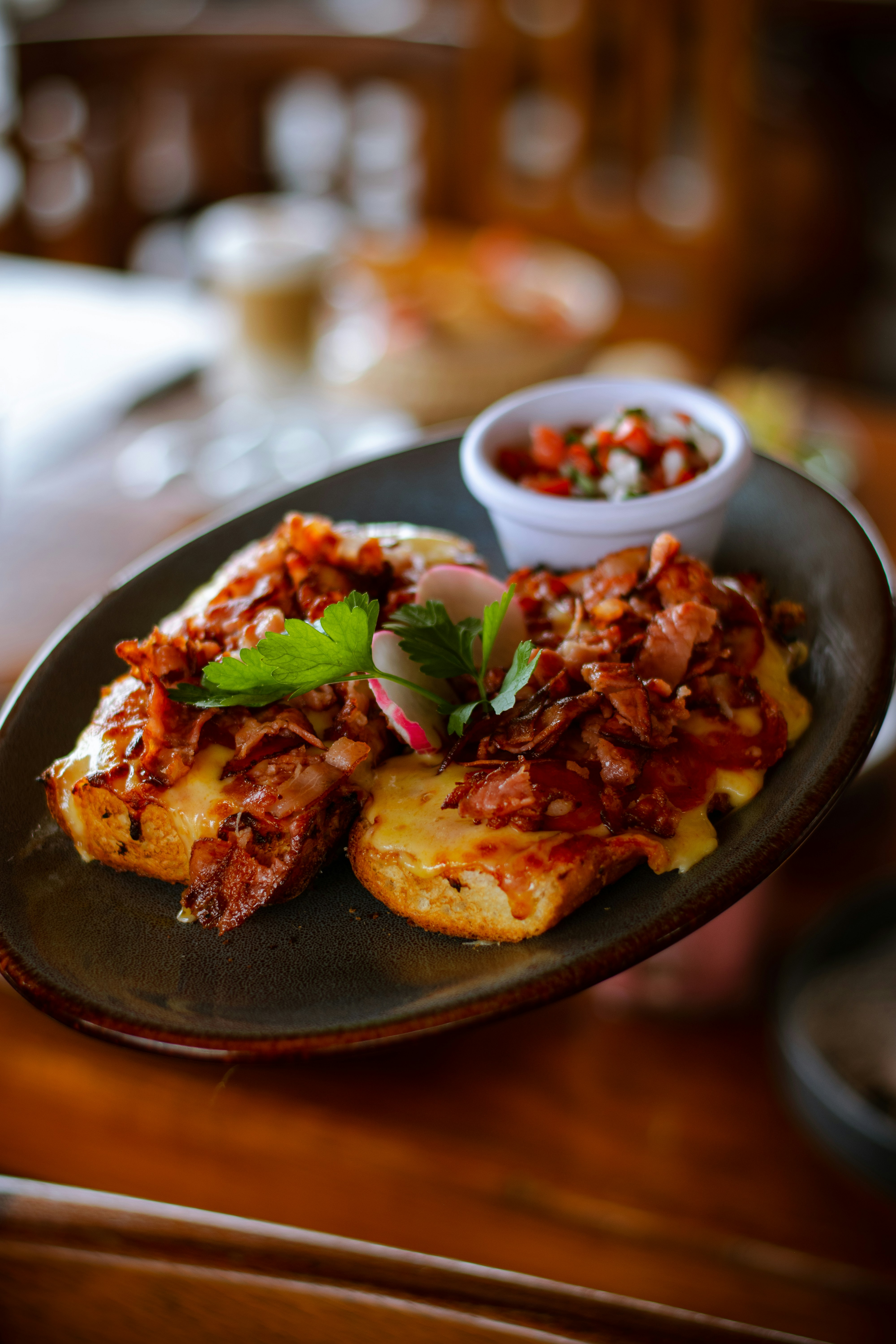 Crispy bacon-topped toasts with a herb garnish and a small salsa side