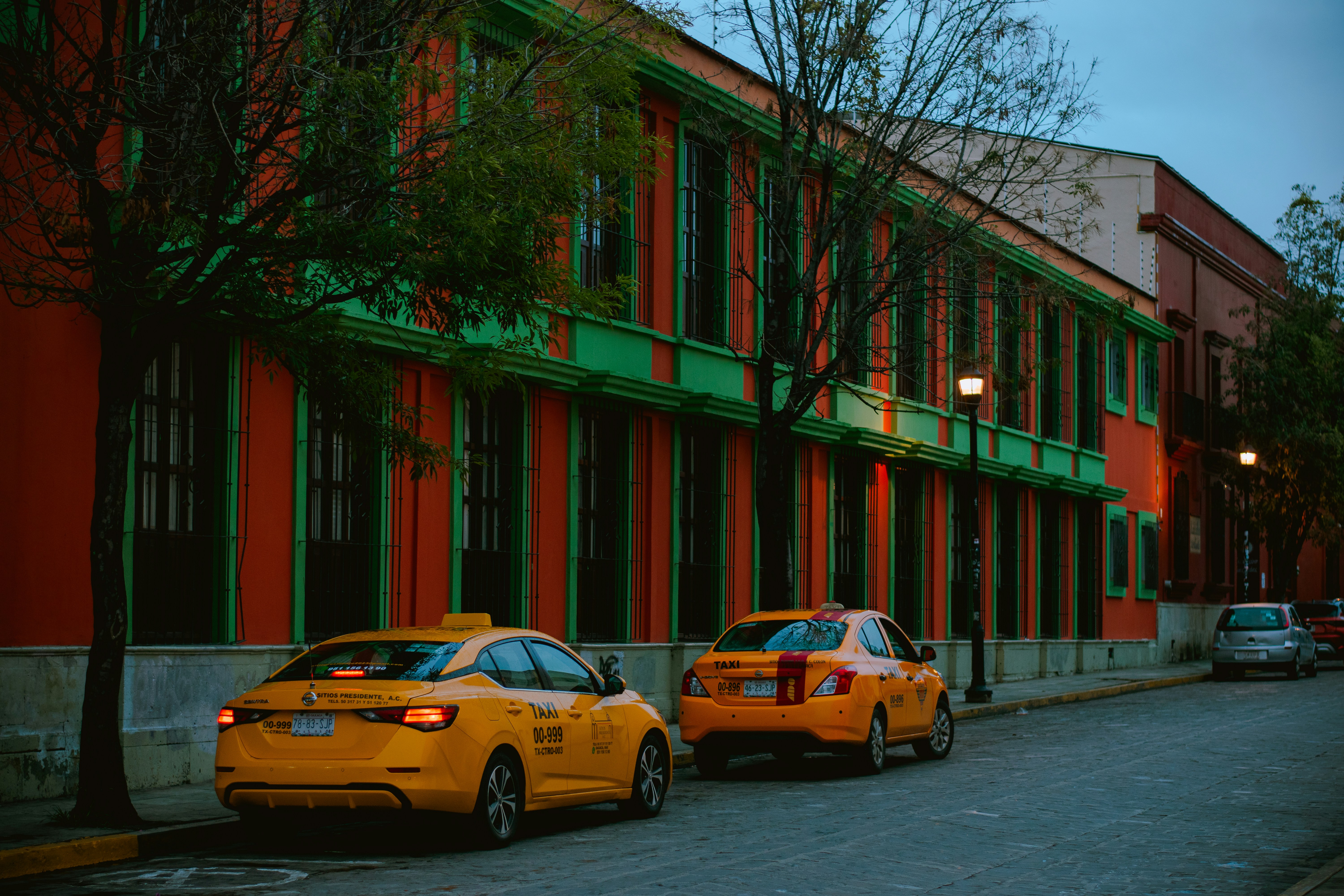 Yellow taxis and a green-washed street under dusky urban glow