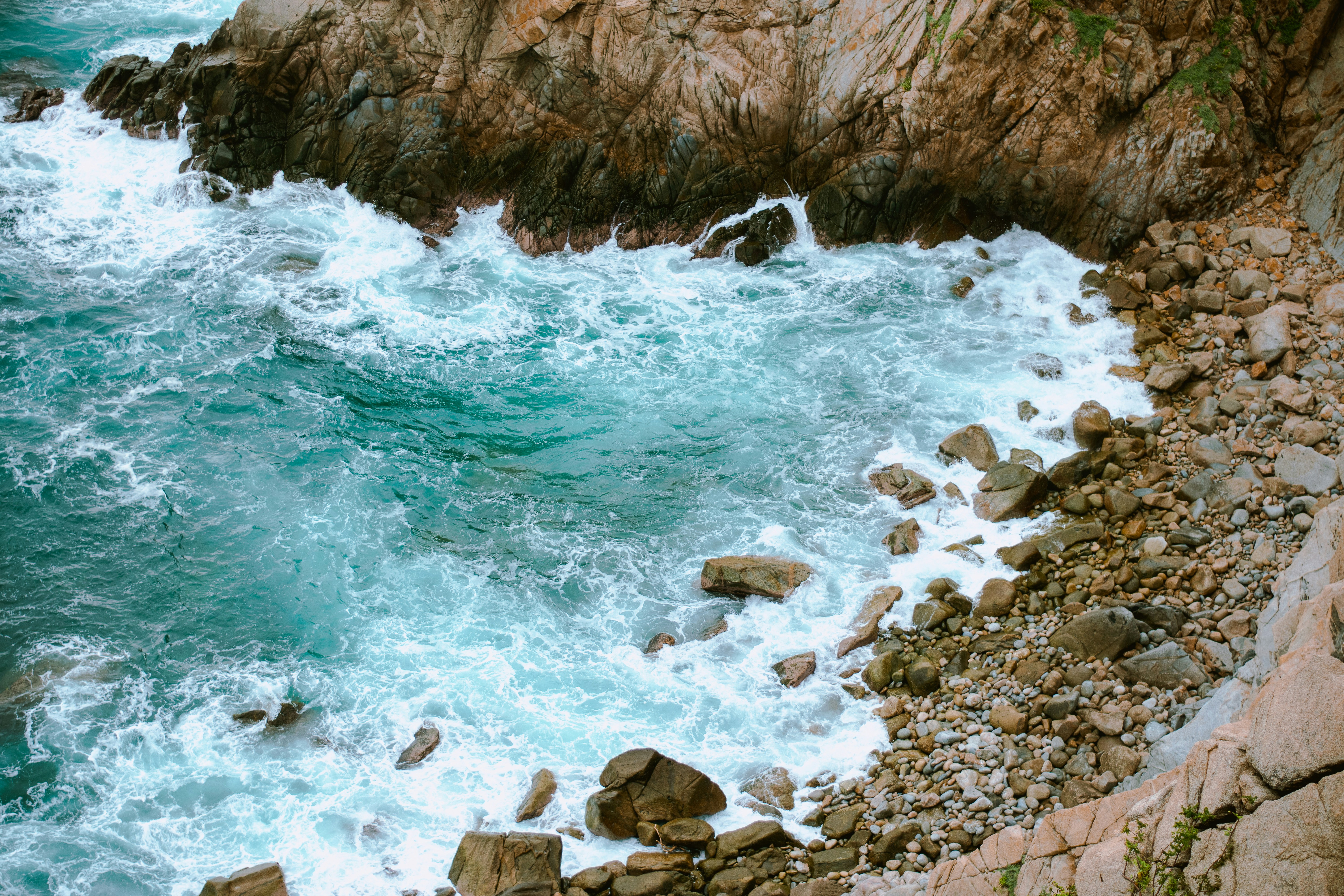 Turquoise crested waves folding over rugged shoreline