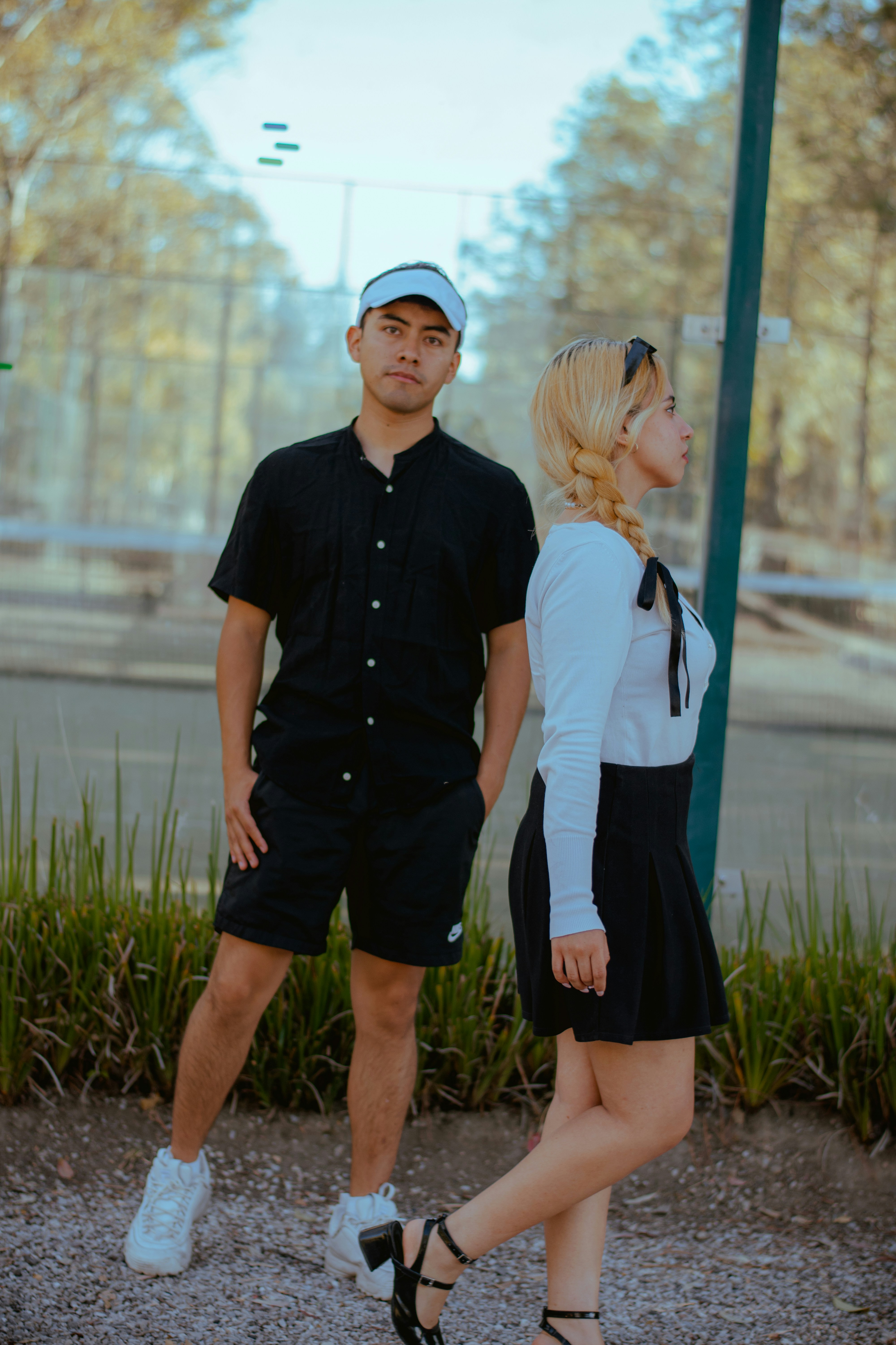 Two Friends Stand in a Sunny Outdoor Court, Contrasting Styles and Directions