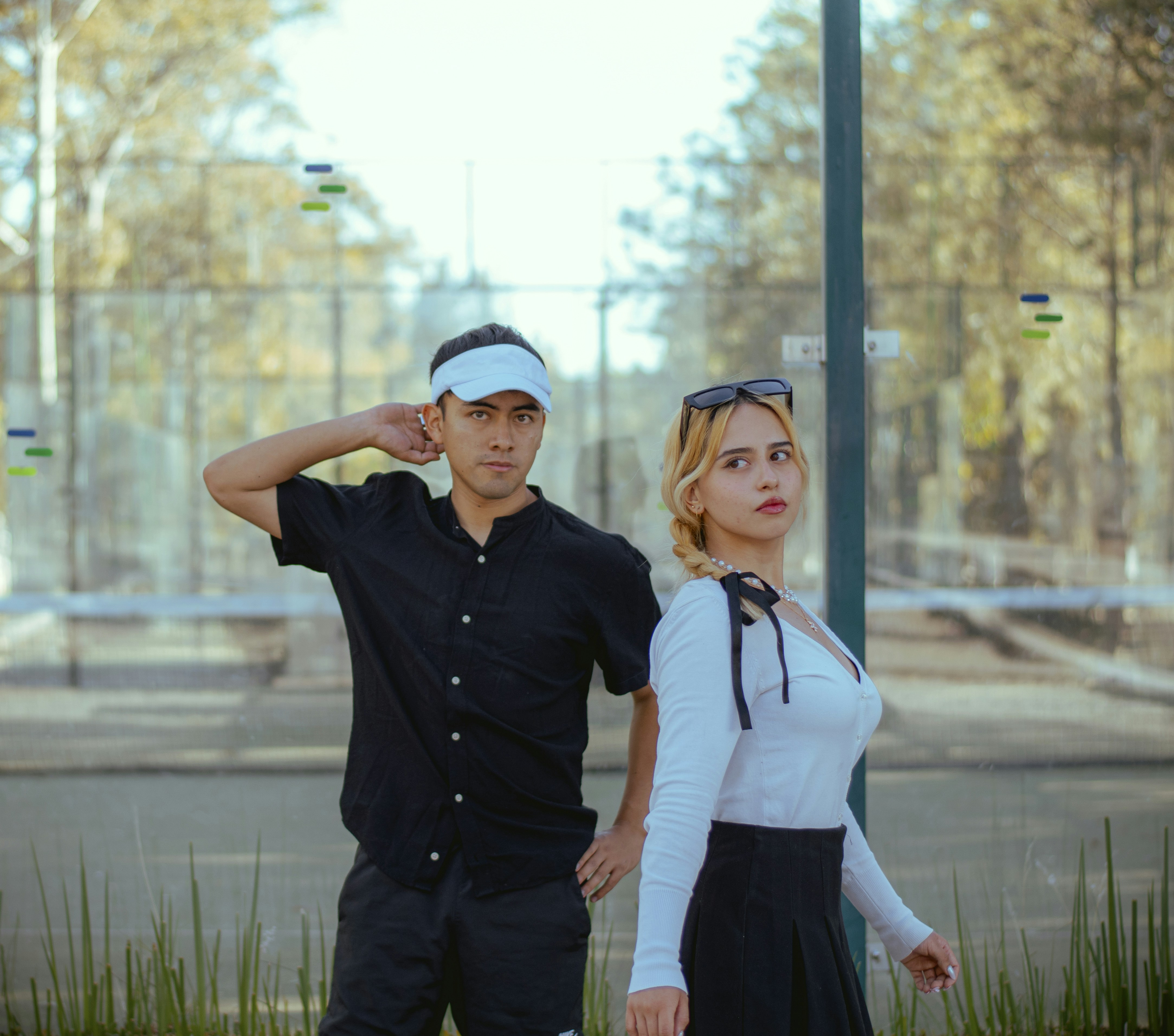 Two Friends Stand Confidently at a Glass-Backed Park