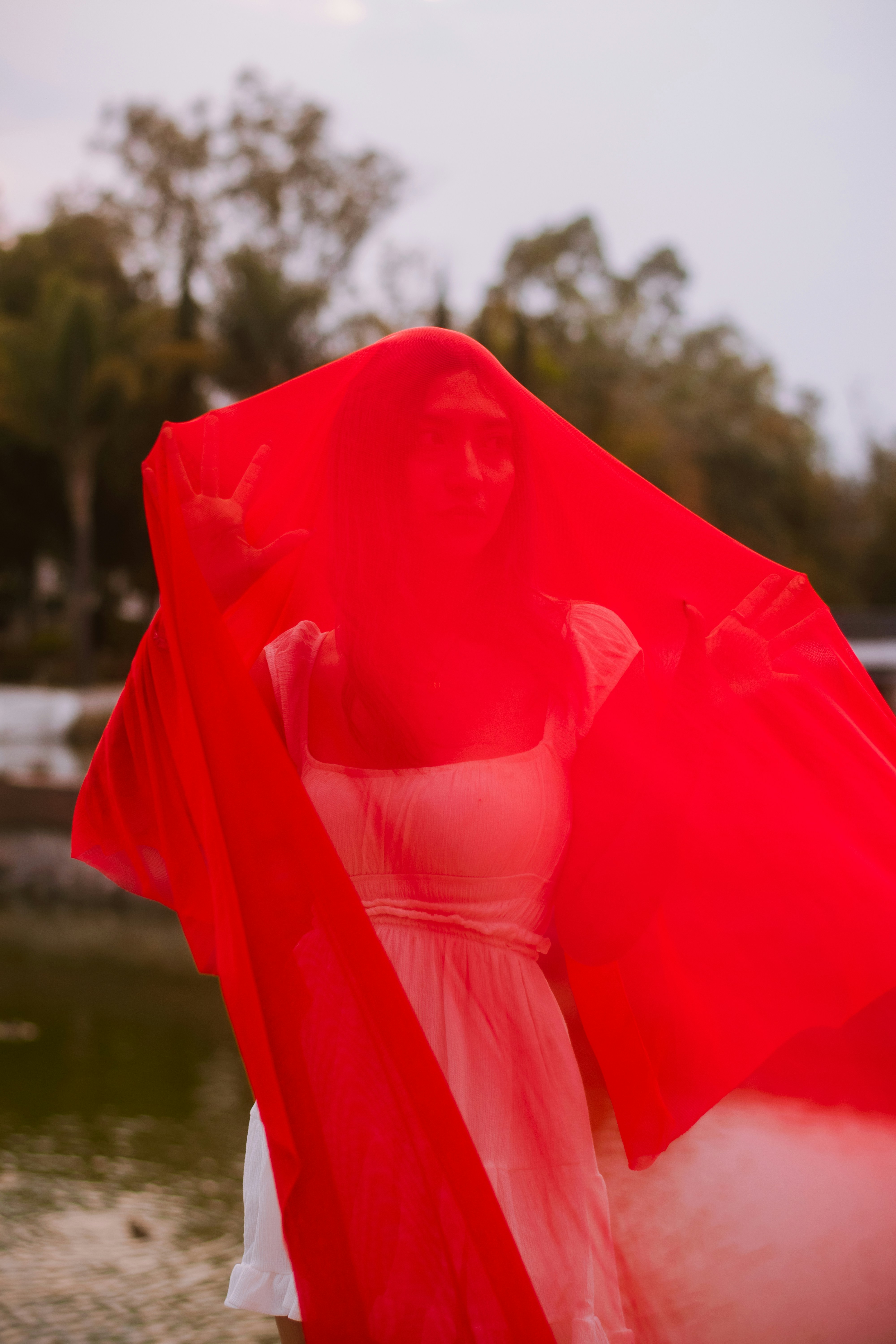 Red Veil, Quiet Pose: A Veiled Portrait by the Water