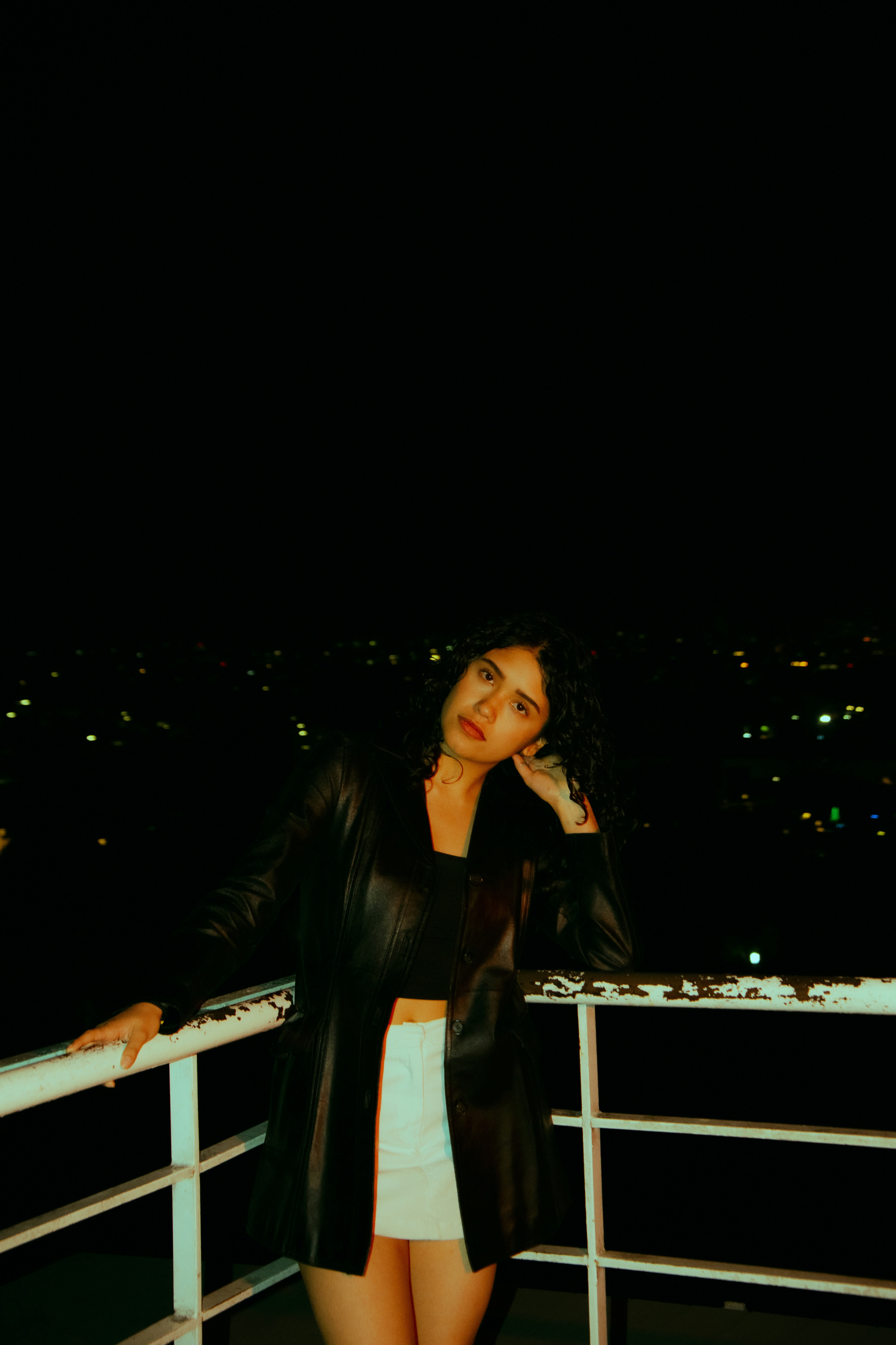 Nighttime rooftop portrait: a confident gaze by city lights
