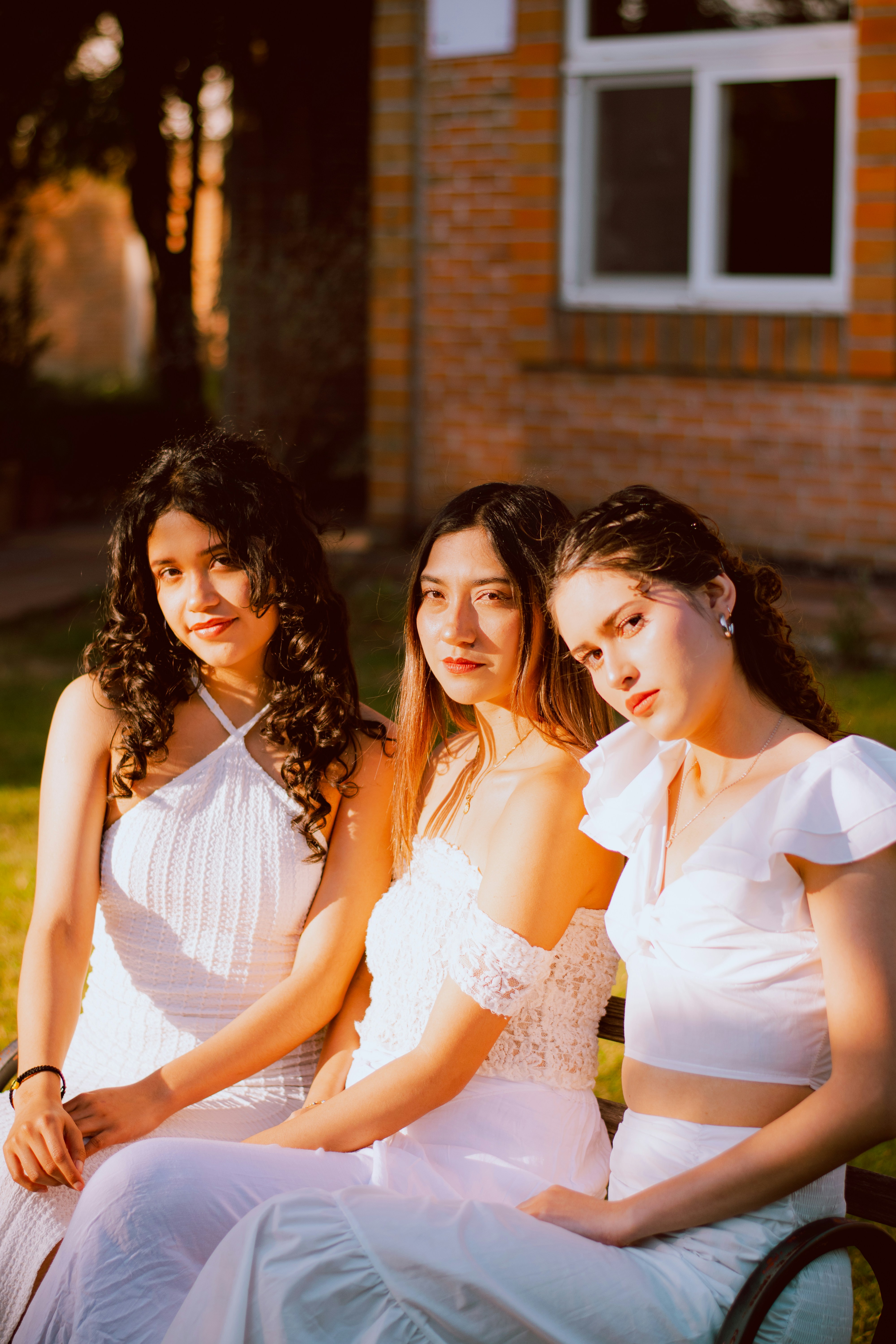 Sunlit Trio in White: Evening Portrait by the Brick Wall