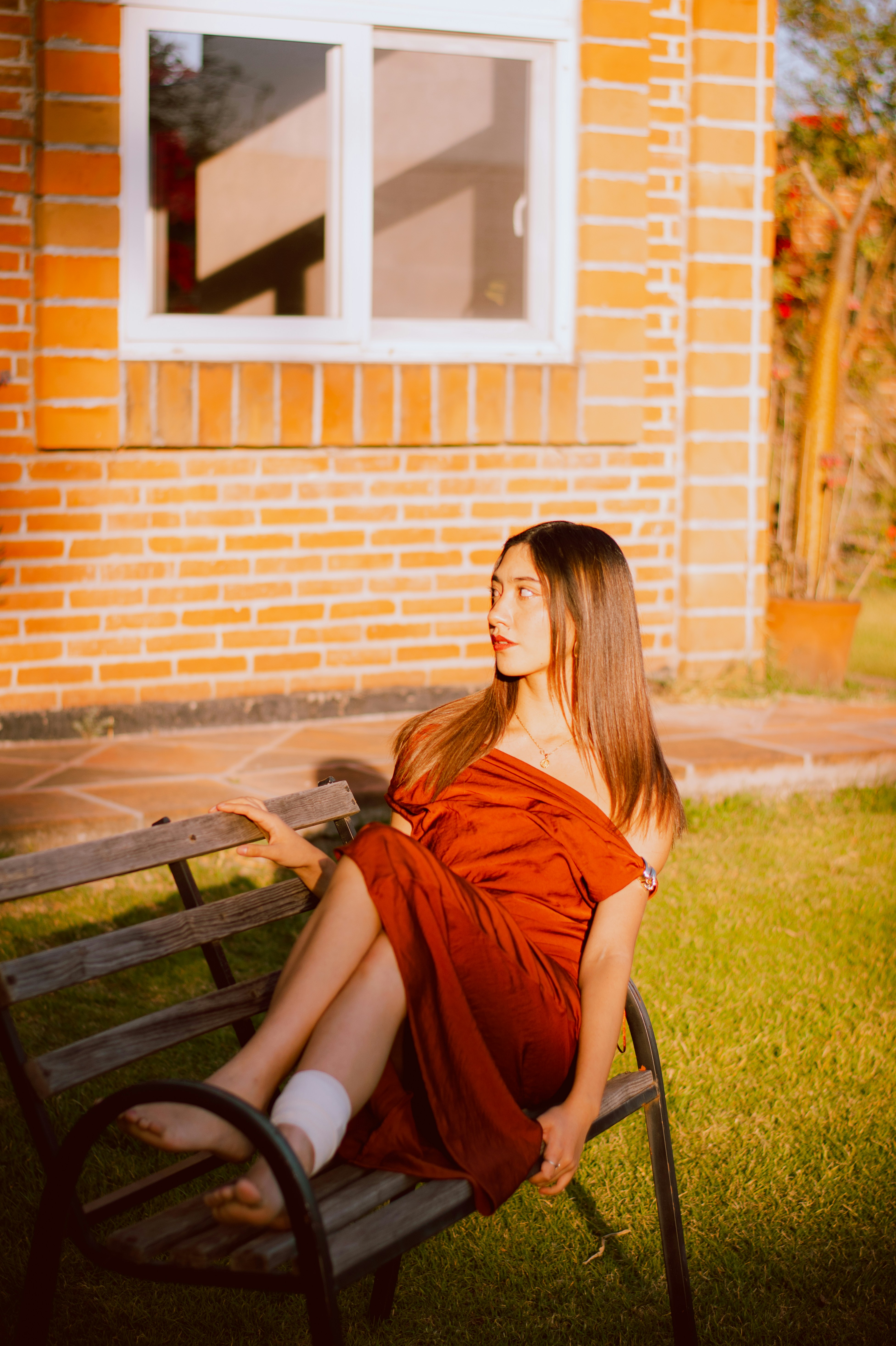 Sunlit Red Dress on a Bench: A Quiet Moment by the Brick House