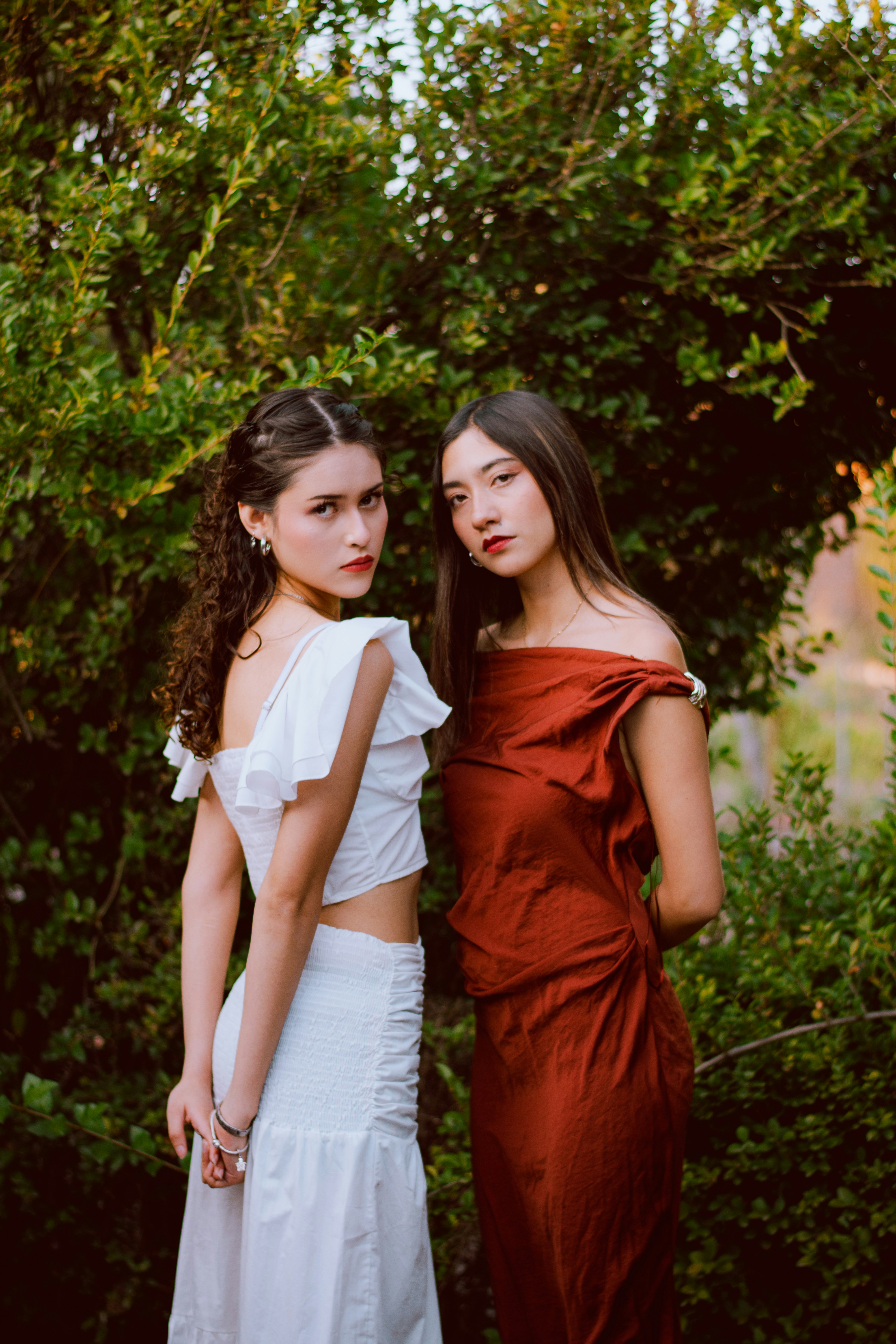Two Contrasting Drapes: White and Rust Pose in a Sunlit Garden