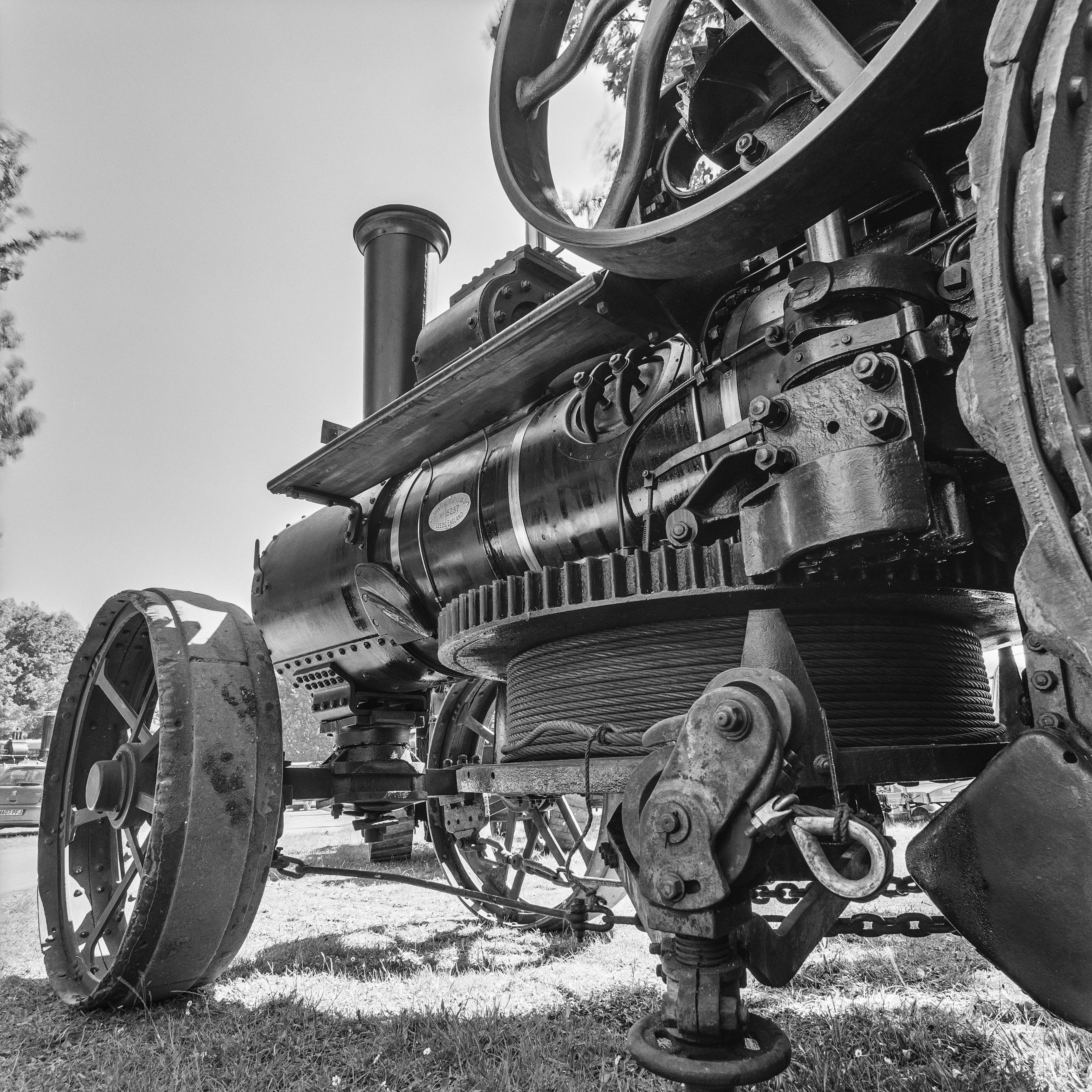 Close-up of an old steam locomotive's mechanical undercarriage, gears and wheels exposed in grayscale with strong texture and contrast.