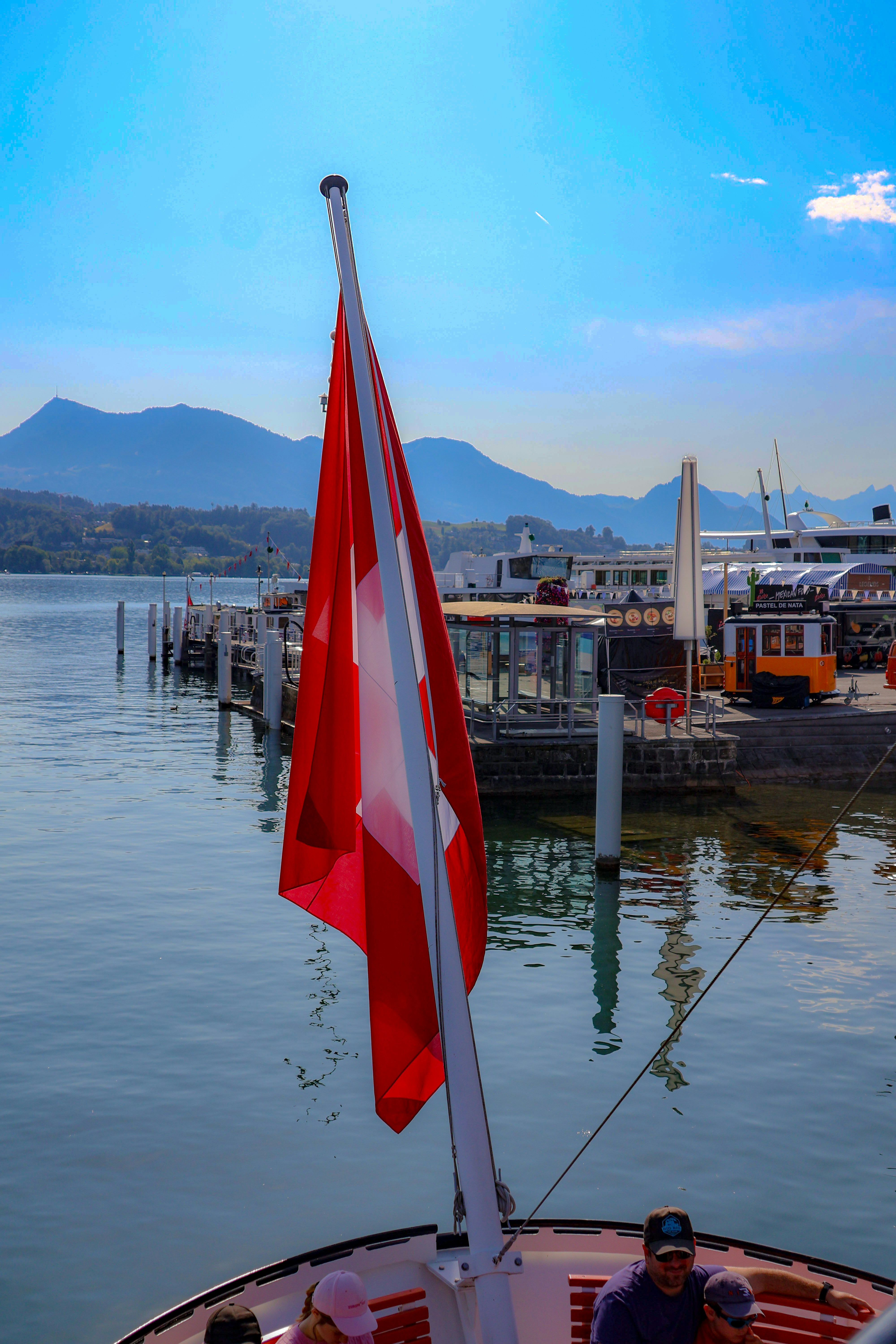 Flagpole of the Swiss Flag Over a Marina at Dusk