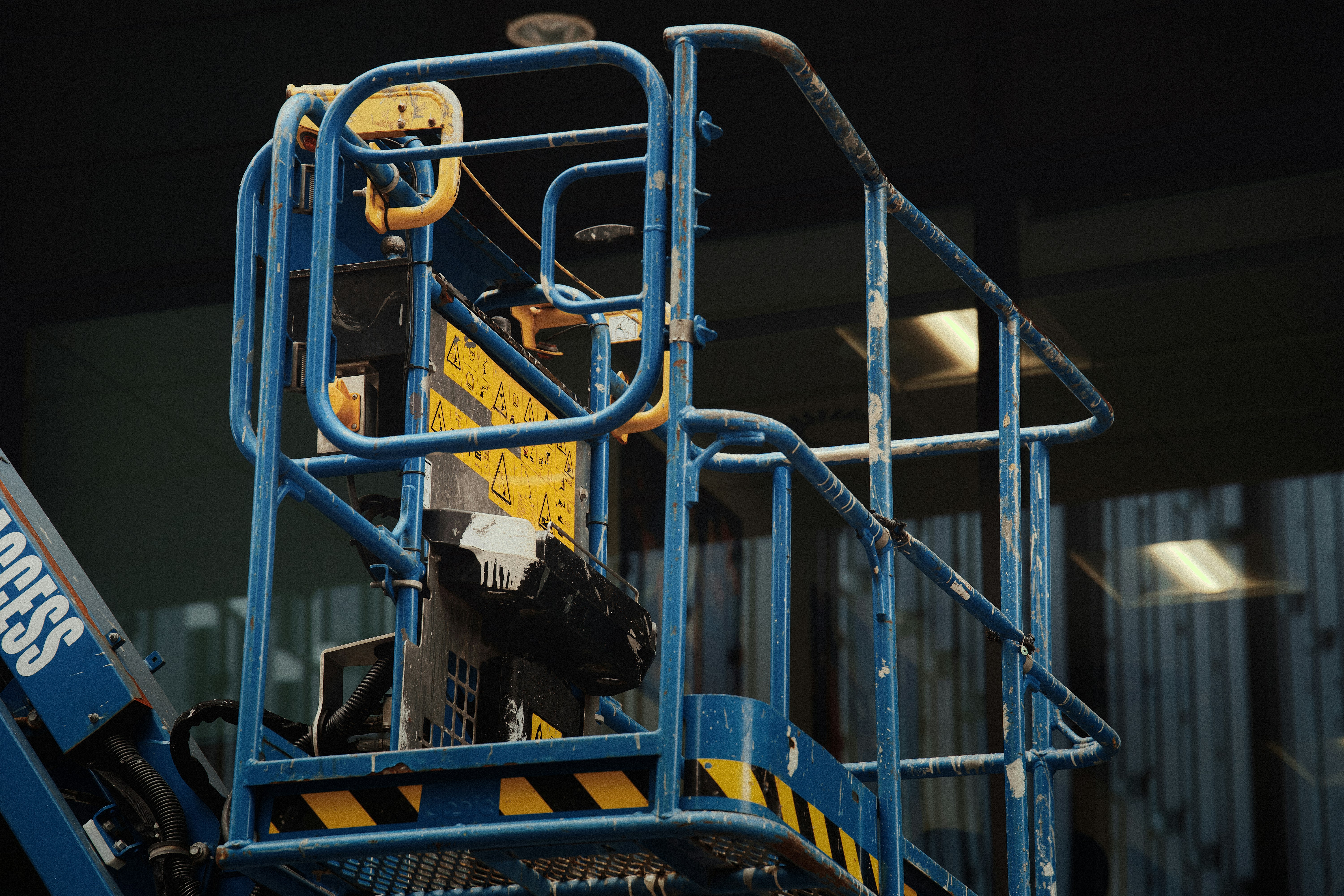 Blue Industrial Scissor Lift Framed by Office Building Corridor