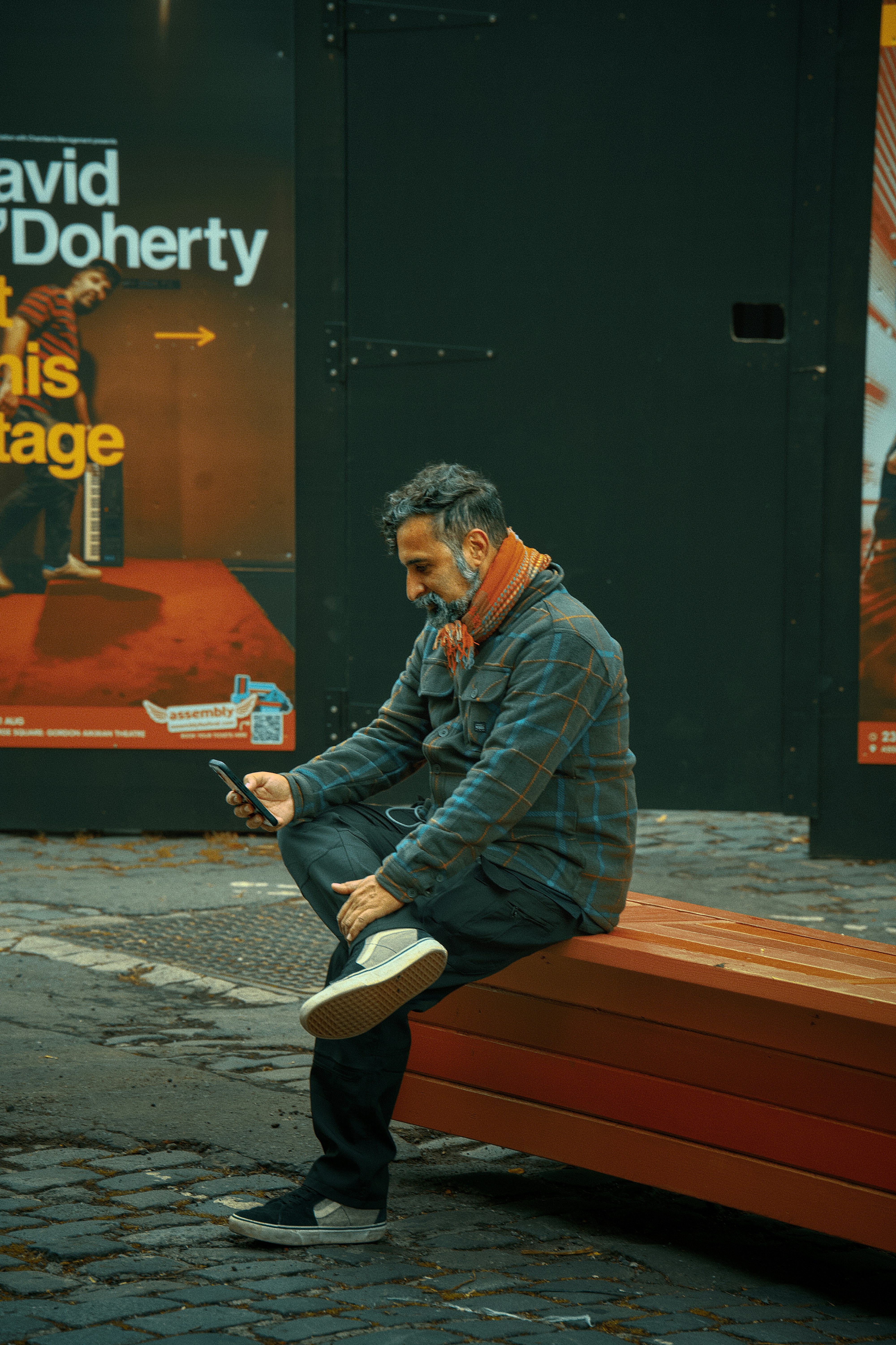 Man on a bench with a tablet in an urban setting