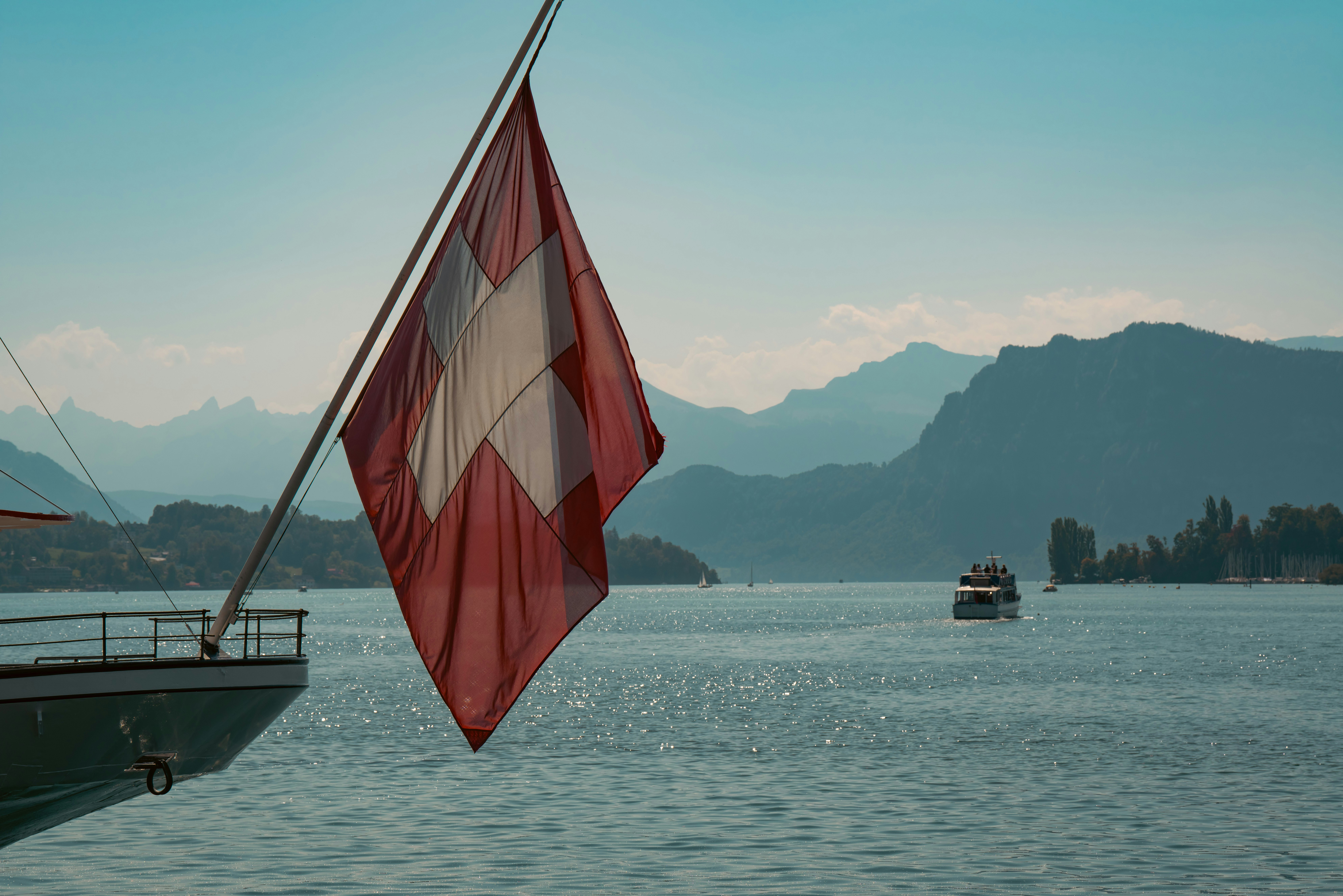 Flag and Sail: A Quiet Moment on a Lake Looming with Distant Peaks
