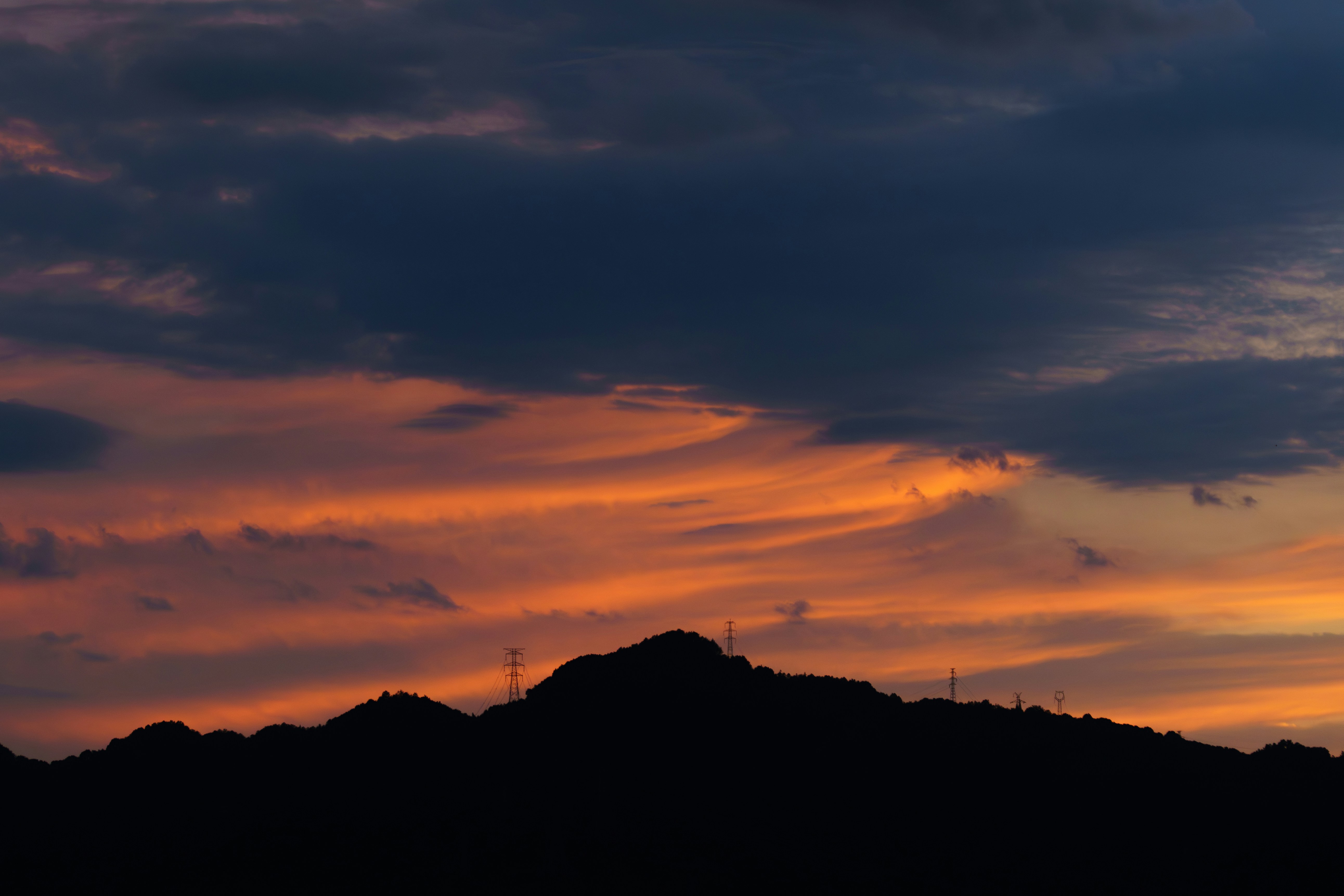 Twilight Ridge: Silhouetted Horizon Beneath Fiery Clouds